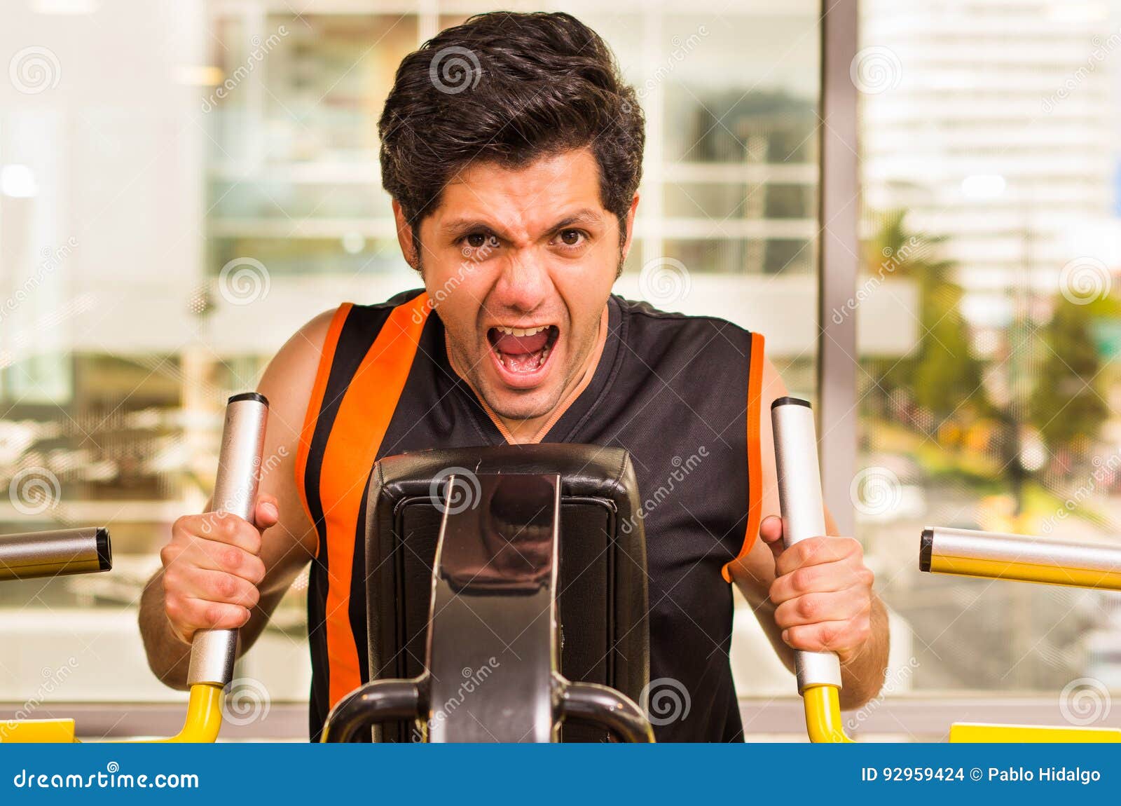 Handsome Young Man Working on Fitness Machine at Gym and Screaming at ...