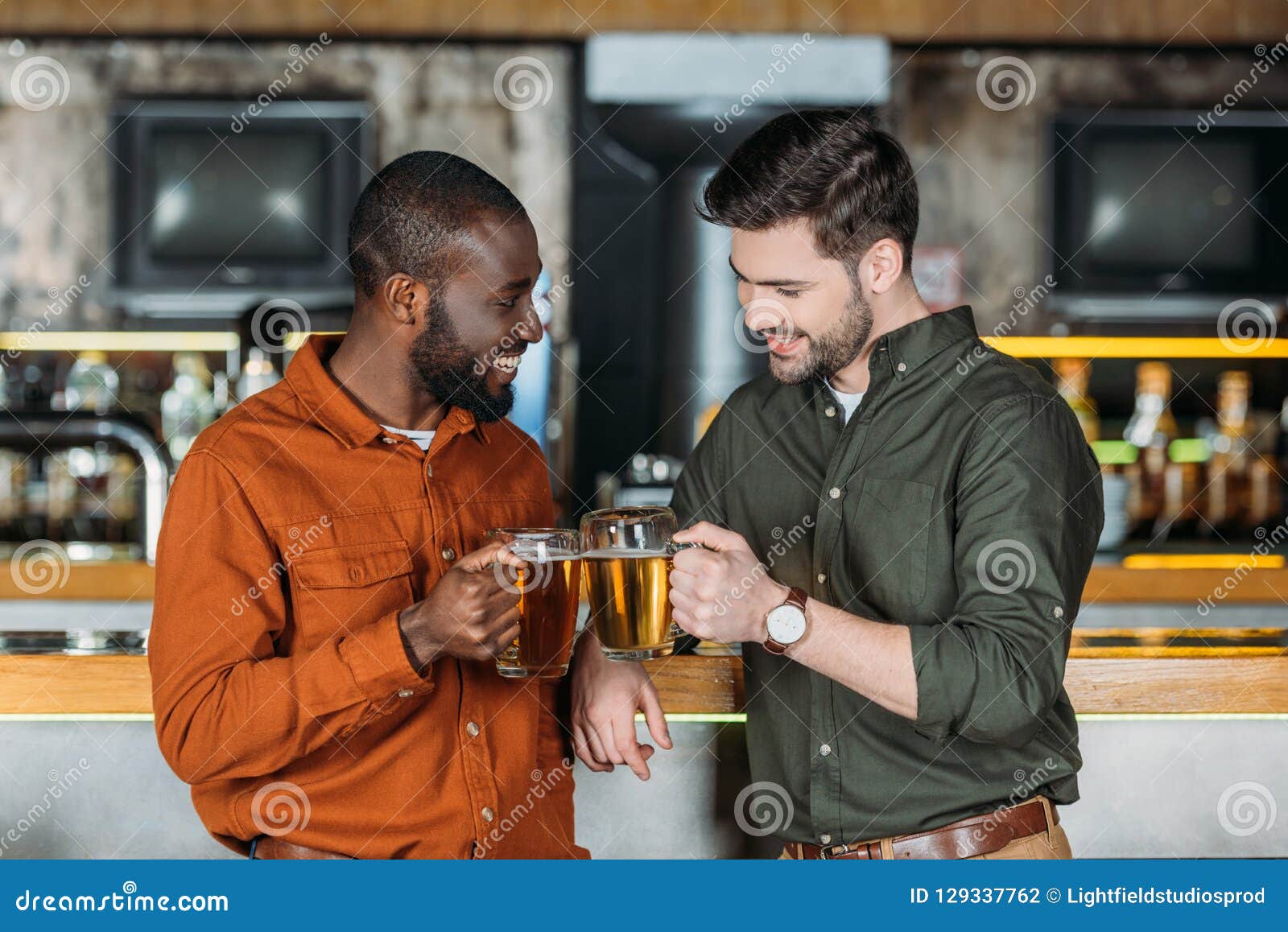 Handsome Young Men with Mugs of Beer Clinking Stock Photo - Image of ...