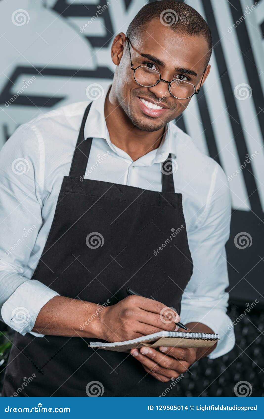 Handsome Young Waiter Writing in Notepad and Looking Stock Photo ...