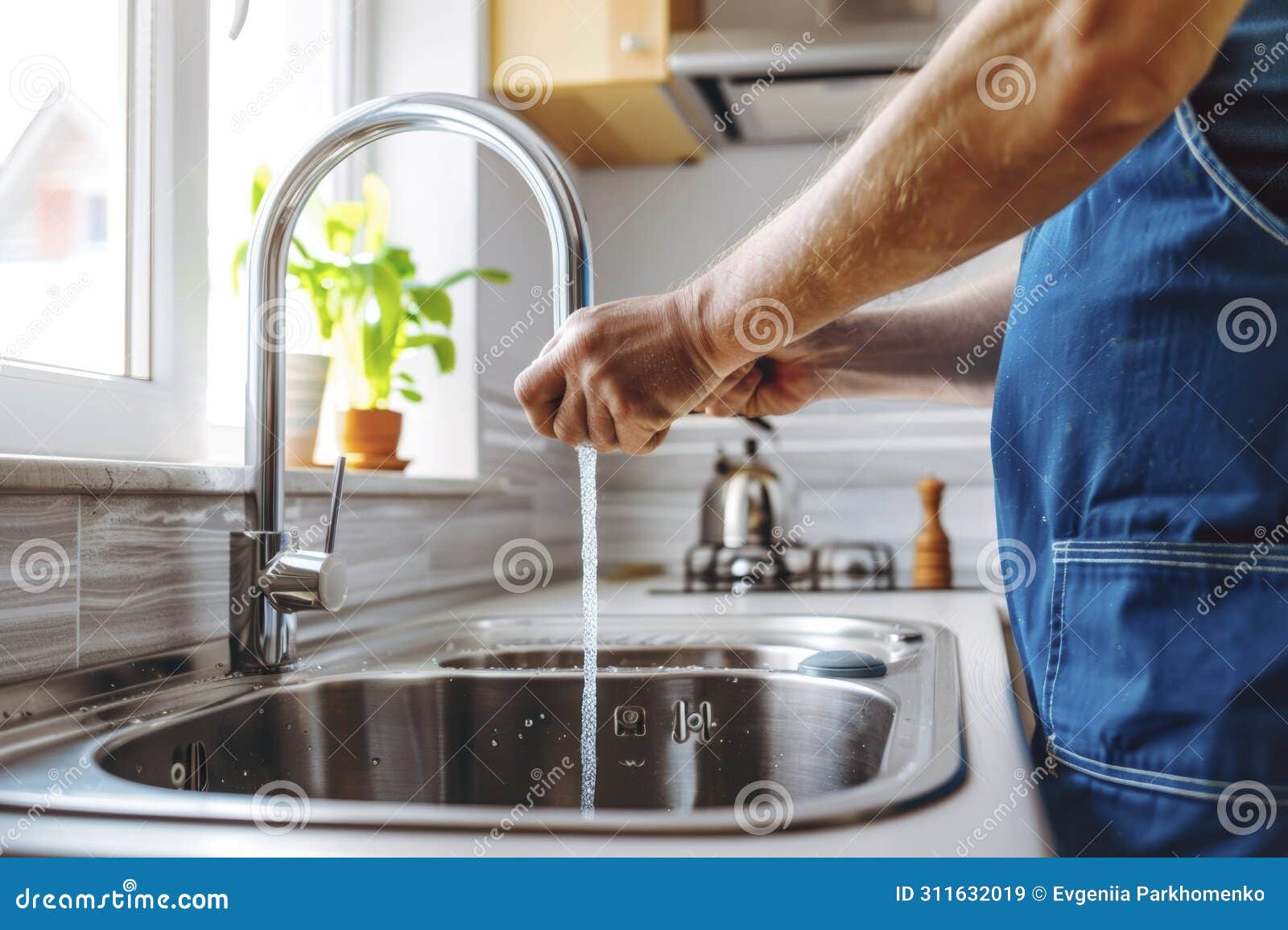 A Handyman Adjusts the Water Flow of a Kitchen Sink Tap, Ensuring ...
