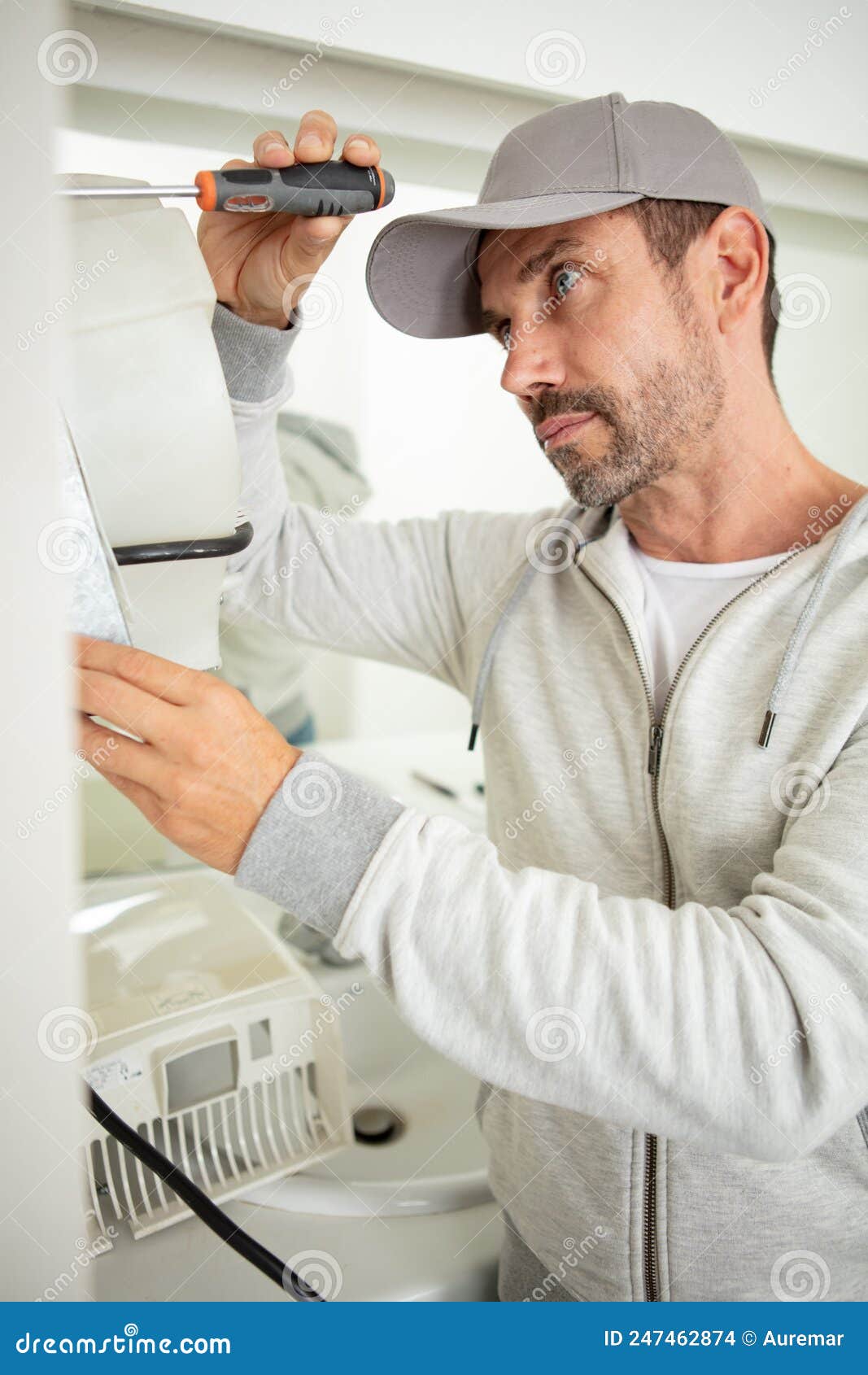 Handyman Wearing Cap Using Screwdriver Stock Photo - Image of handyman ...