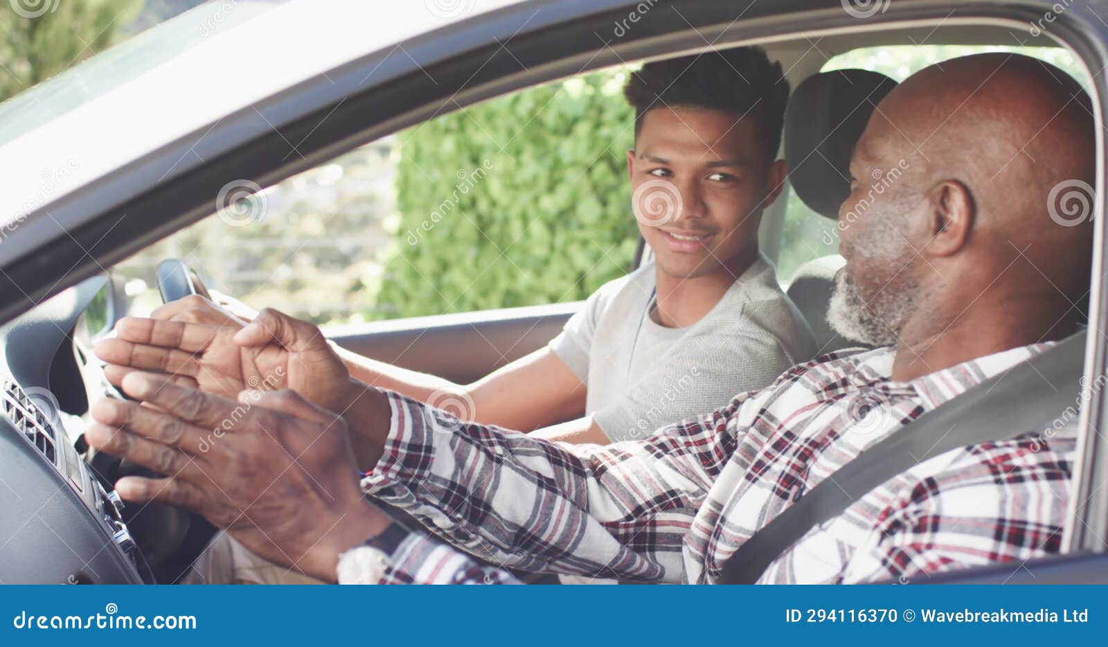 Happy African American Father Instructing Smiling Son In Car Before