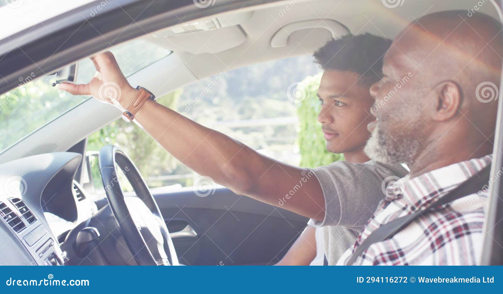 Happy African American Father Instructing Son About Mirror In Car