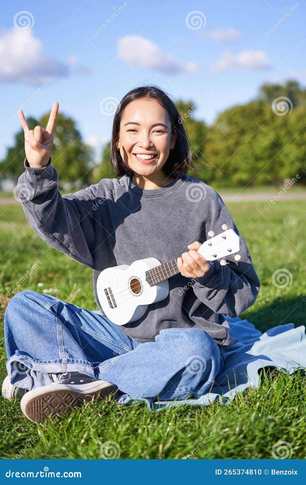 Happy Asian Girl Playing Ukulele In Park Showing Rock N Roll Heavy