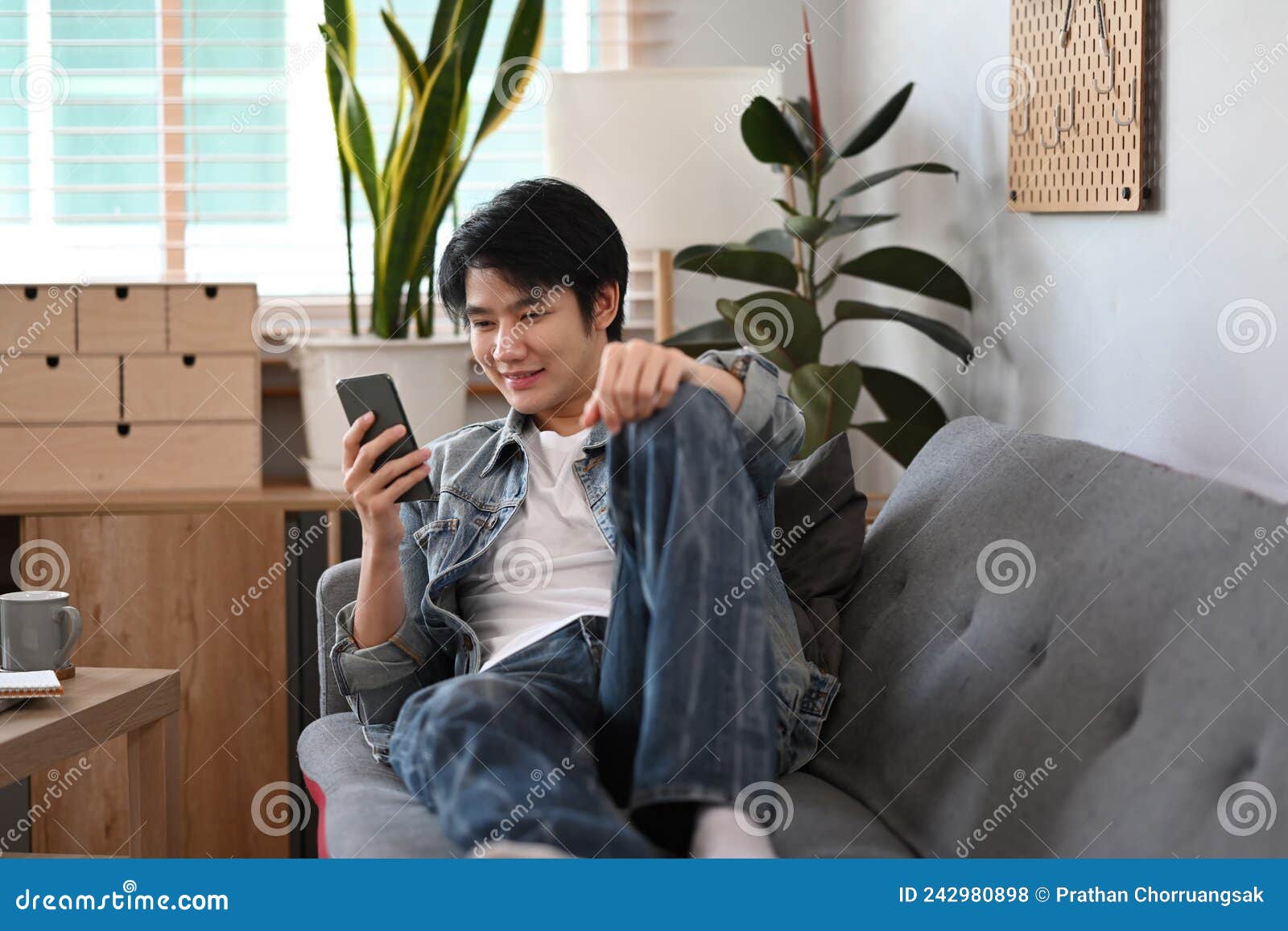 Happy Asian Man Lying on Couch at Home and Using Smart Phone. Stock ...
