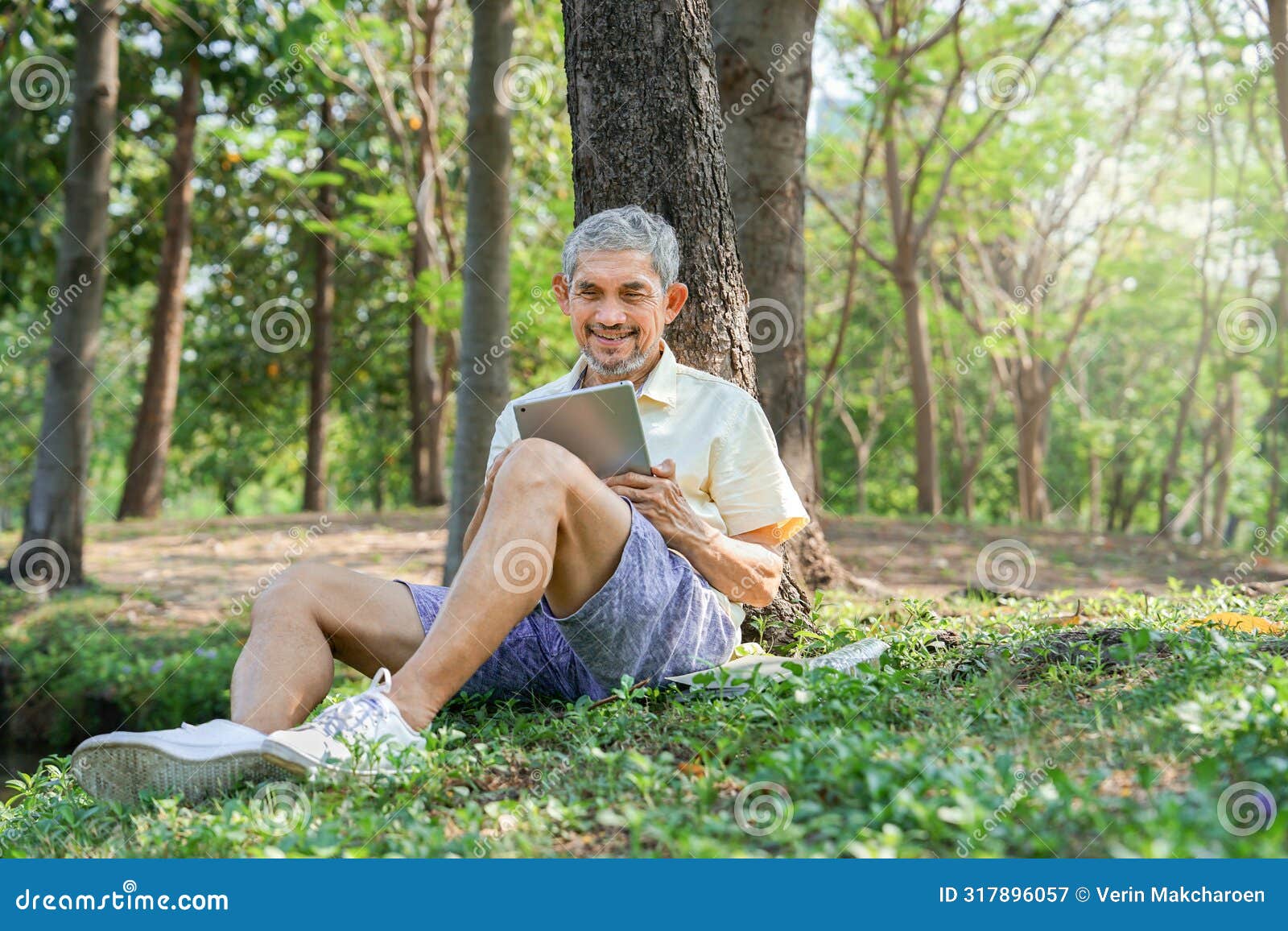 Happy Asian Senior Man Relaxing Under A Tree In National Park Stock