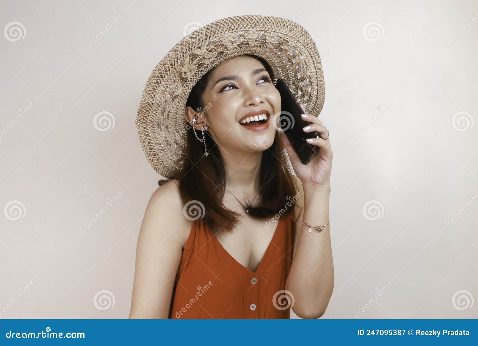 Happy Asian Woman Wearing A Straw Hat Talking On A Mobile Phone And