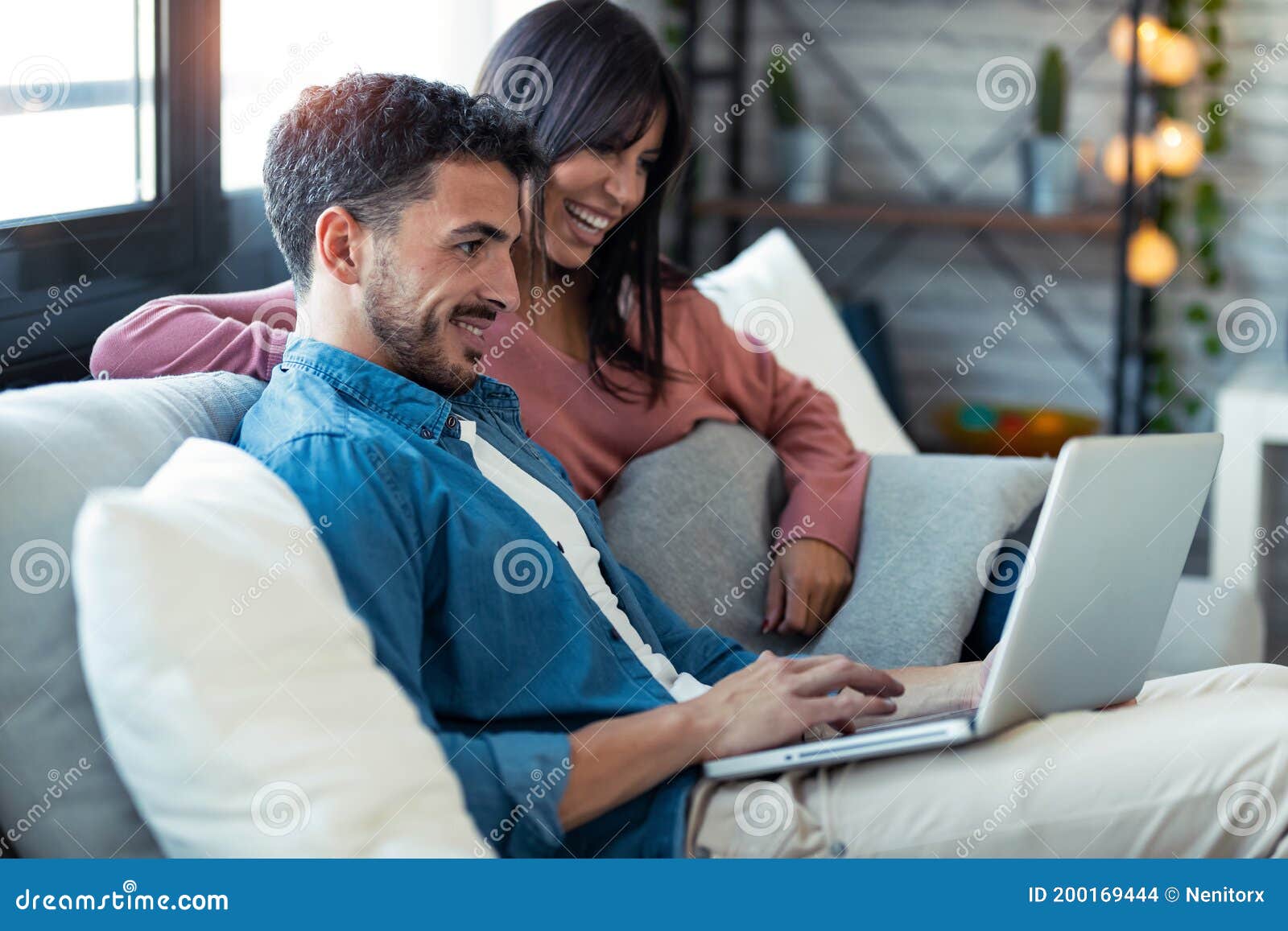 Happy Beautiful Couple Using Computer while Sitting on the Couch at ...