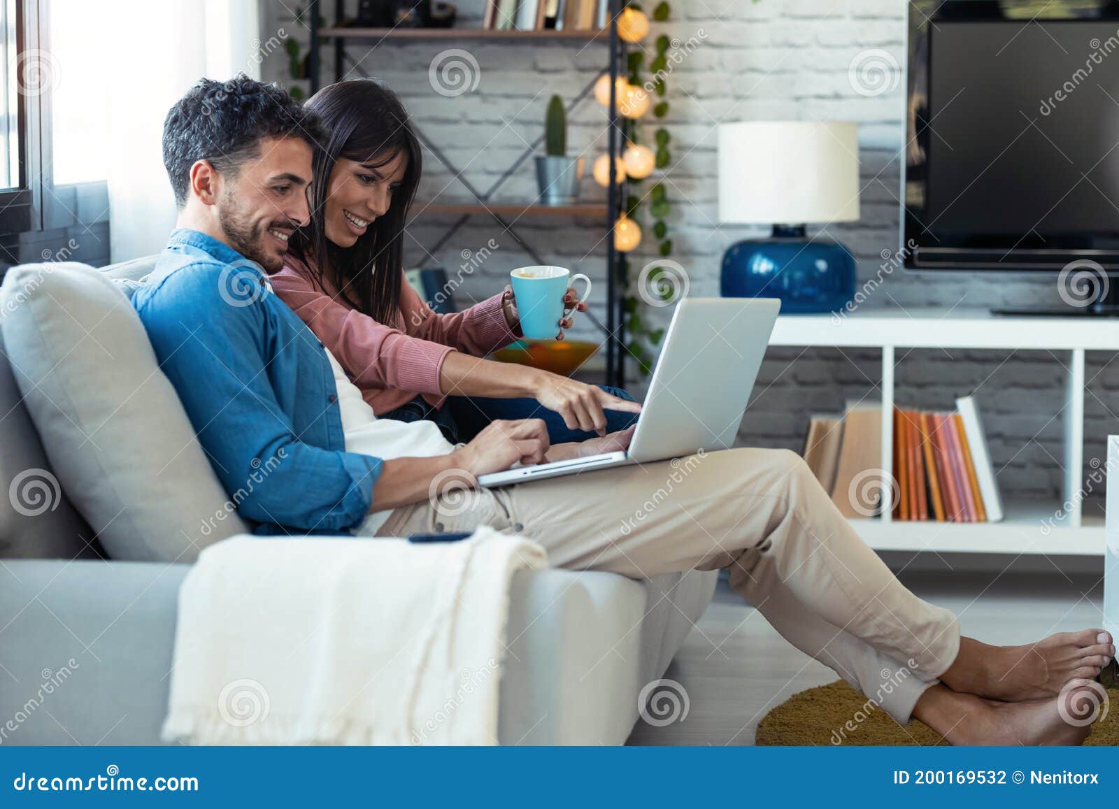 Happy Beautiful Couple Using Computer While Sitting On The Couch At ...
