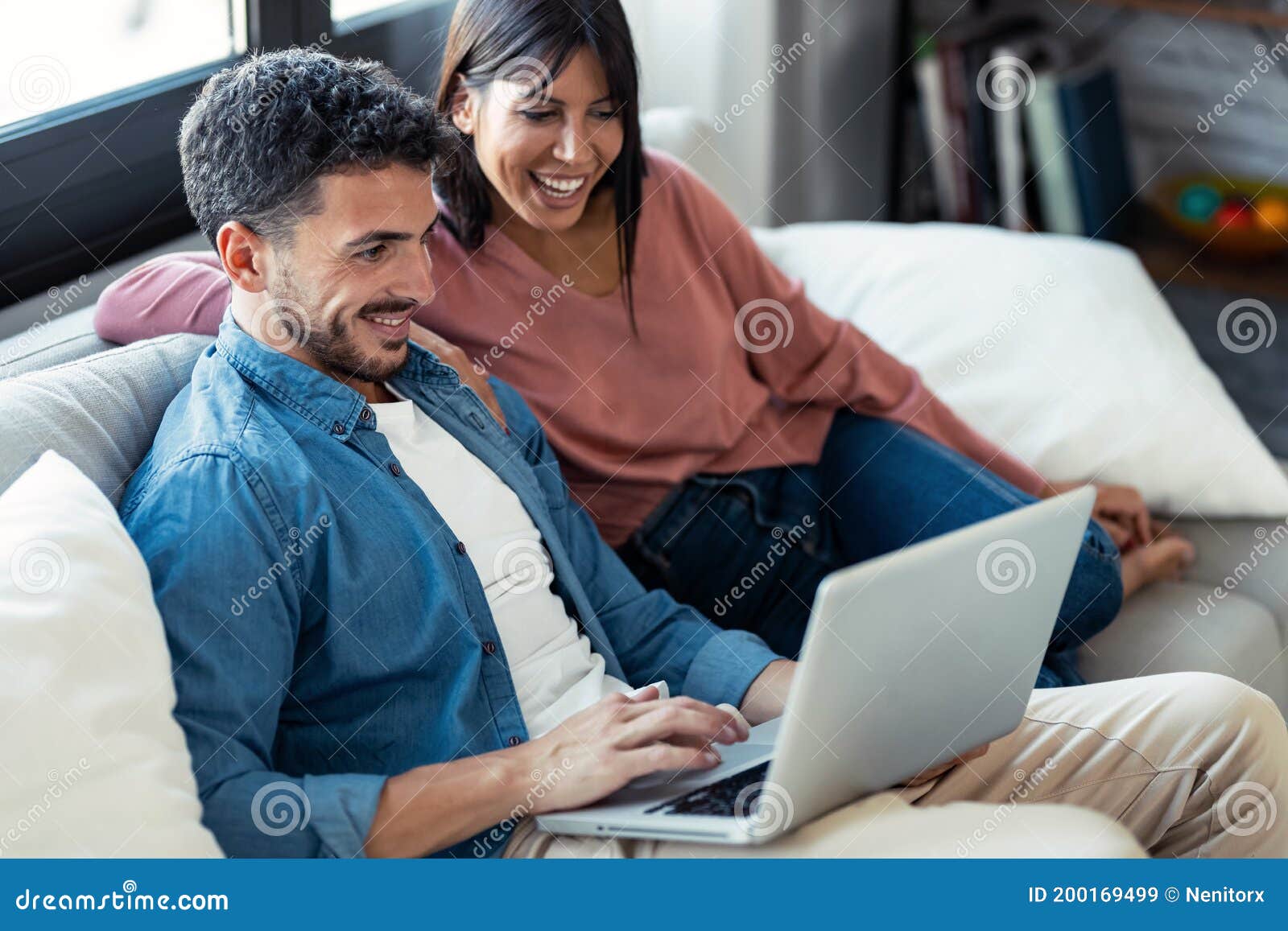 Happy Beautiful Couple Using Computer while Sitting on the Couch at ...