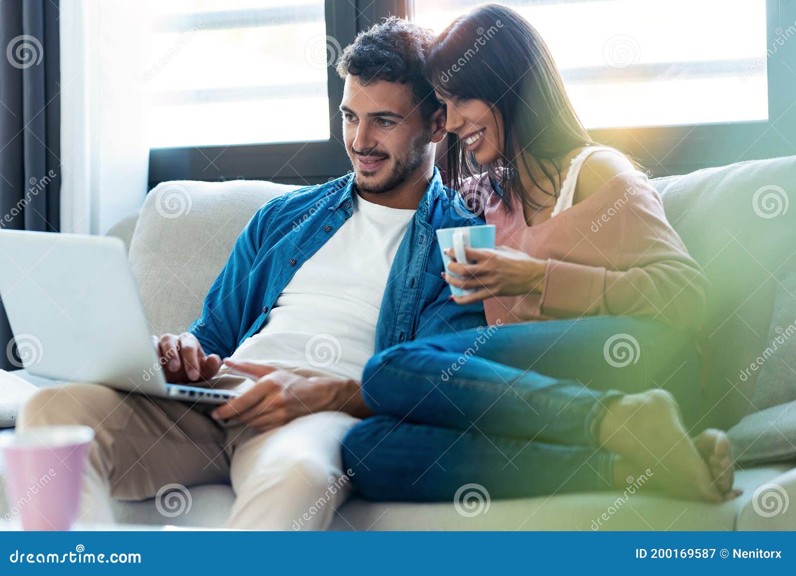 Happy Beautiful Couple Using Computer while Sitting on the Couch at ...