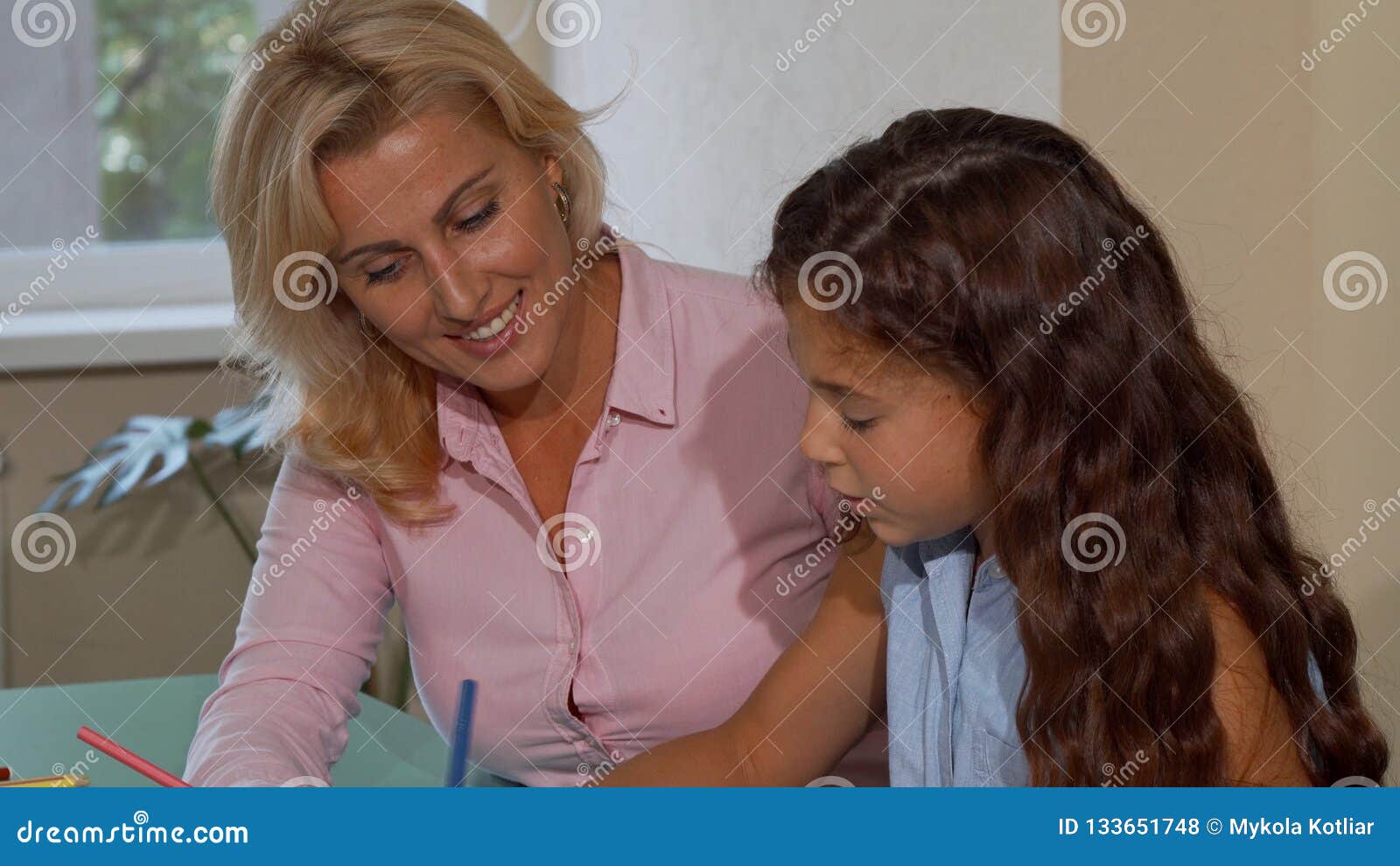 Happy Beautiful Female Teacher Smiling While Helping Her Adorable