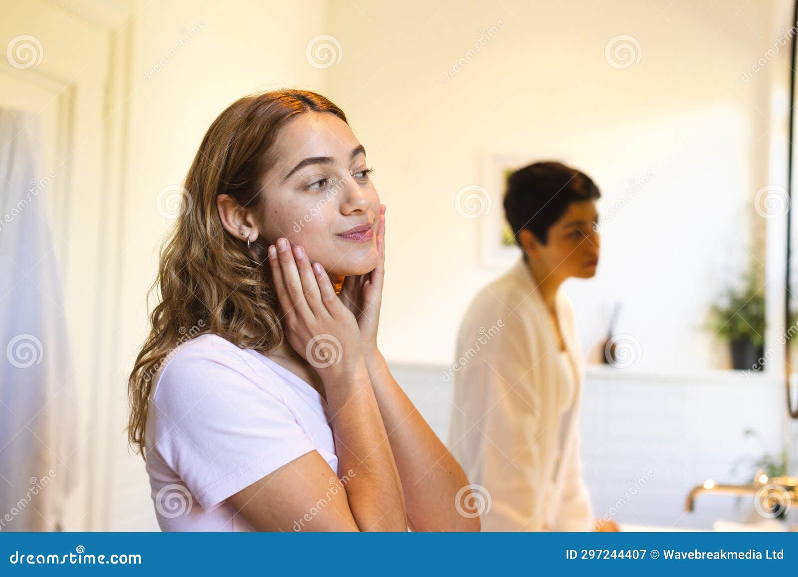 Happy Biracial Lesbian Couple Touching Face And Looking In Bathroom