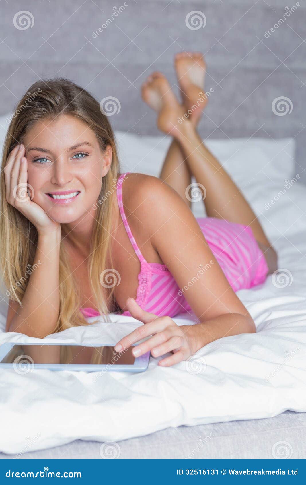 Happy Blonde Lying On Her Bed Using Tablet Pc Smiling At Camera Stock