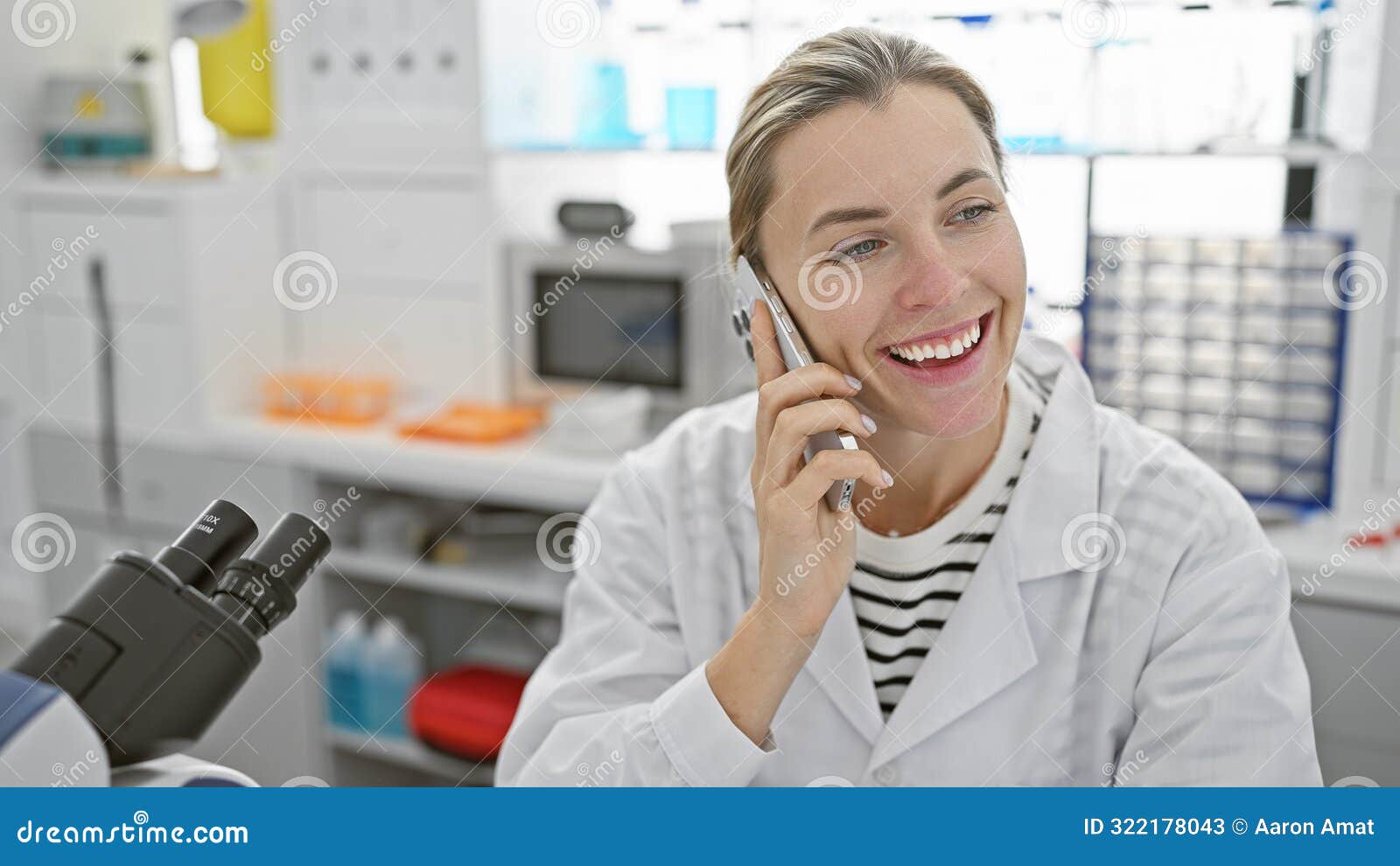 Happy Blonde Woman in White Lab Coat Talking on Phone in a Laboratory ...