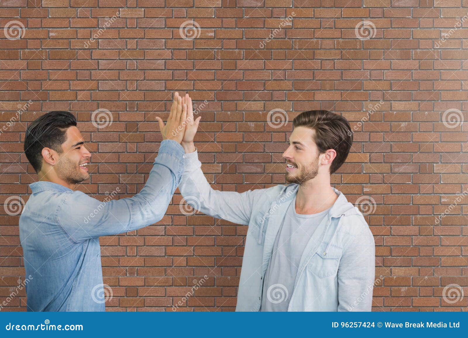 Happy Business Men Doing a High Five Against Brick Wall Stock Photo ...