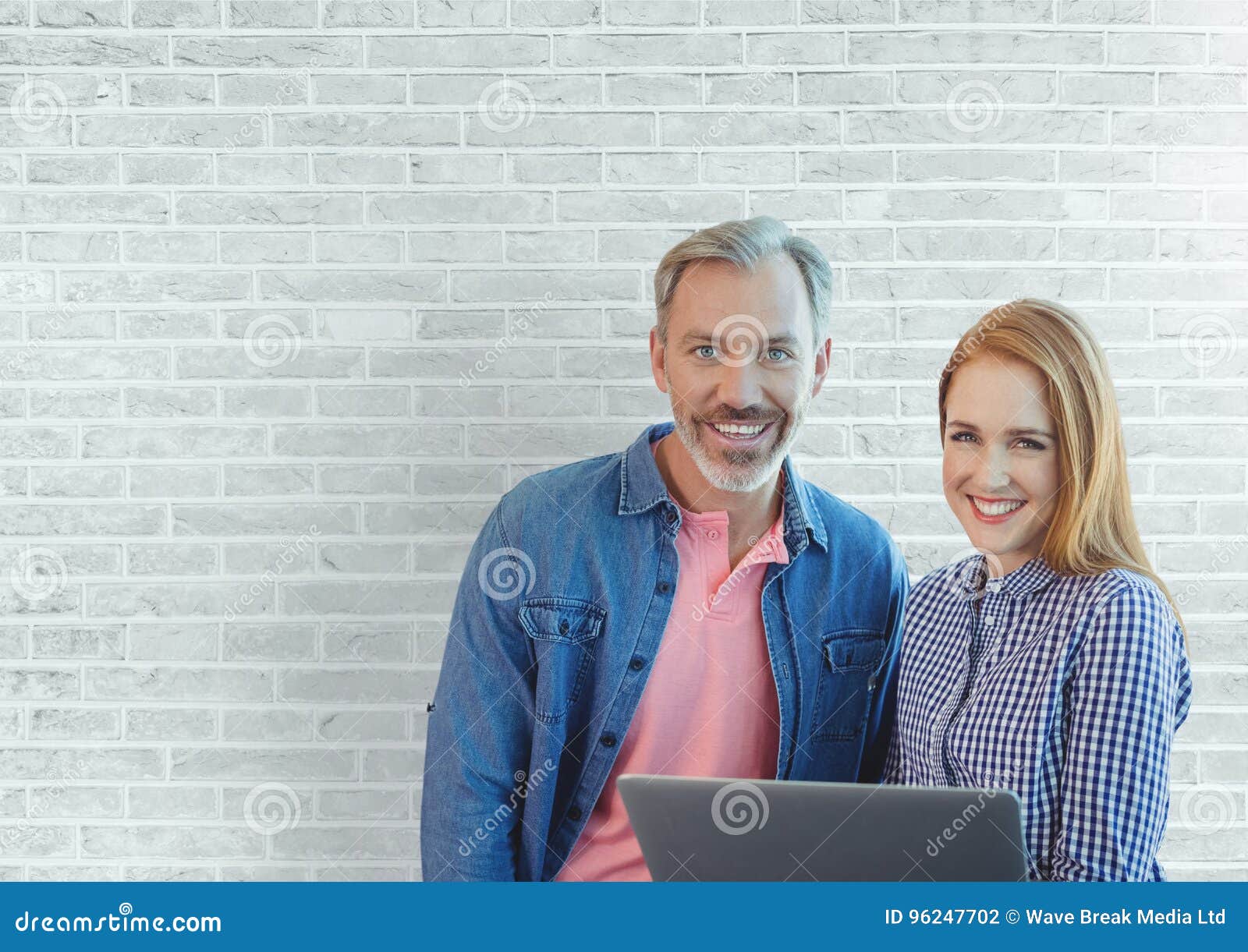 Happy Business People Holding a Computer Against White Wall Stock Photo ...
