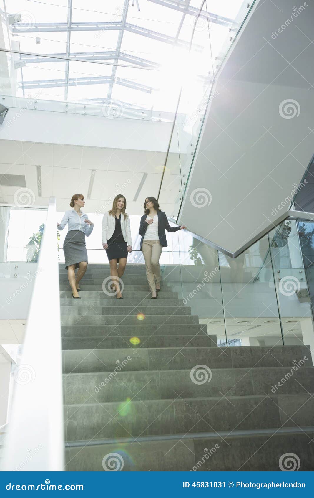 Happy Businesswomen Conversing while Moving Down Steps in Office Stock ...