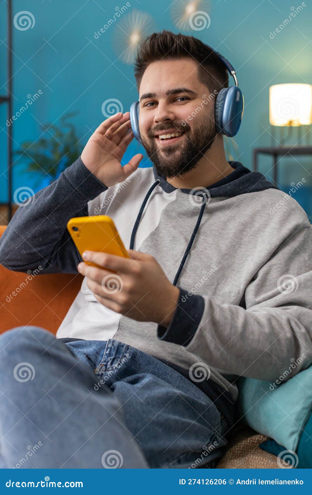Happy Caucasian Man In Wireless Headphones Relaxing Sitting On Sofa At