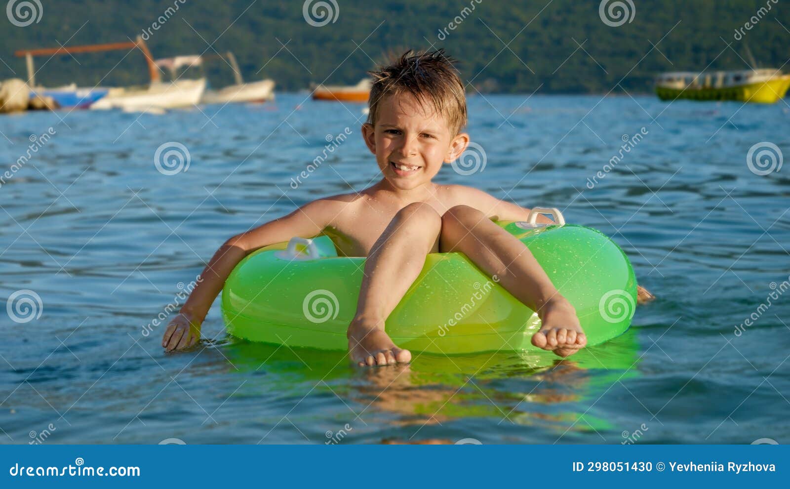 Happy Cheerful Boy Splashing Water while Sitting in Inflatable Ring and ... Happy Cheerful Boy Splashing Water while Sitting in Inflatable Ring and ...
