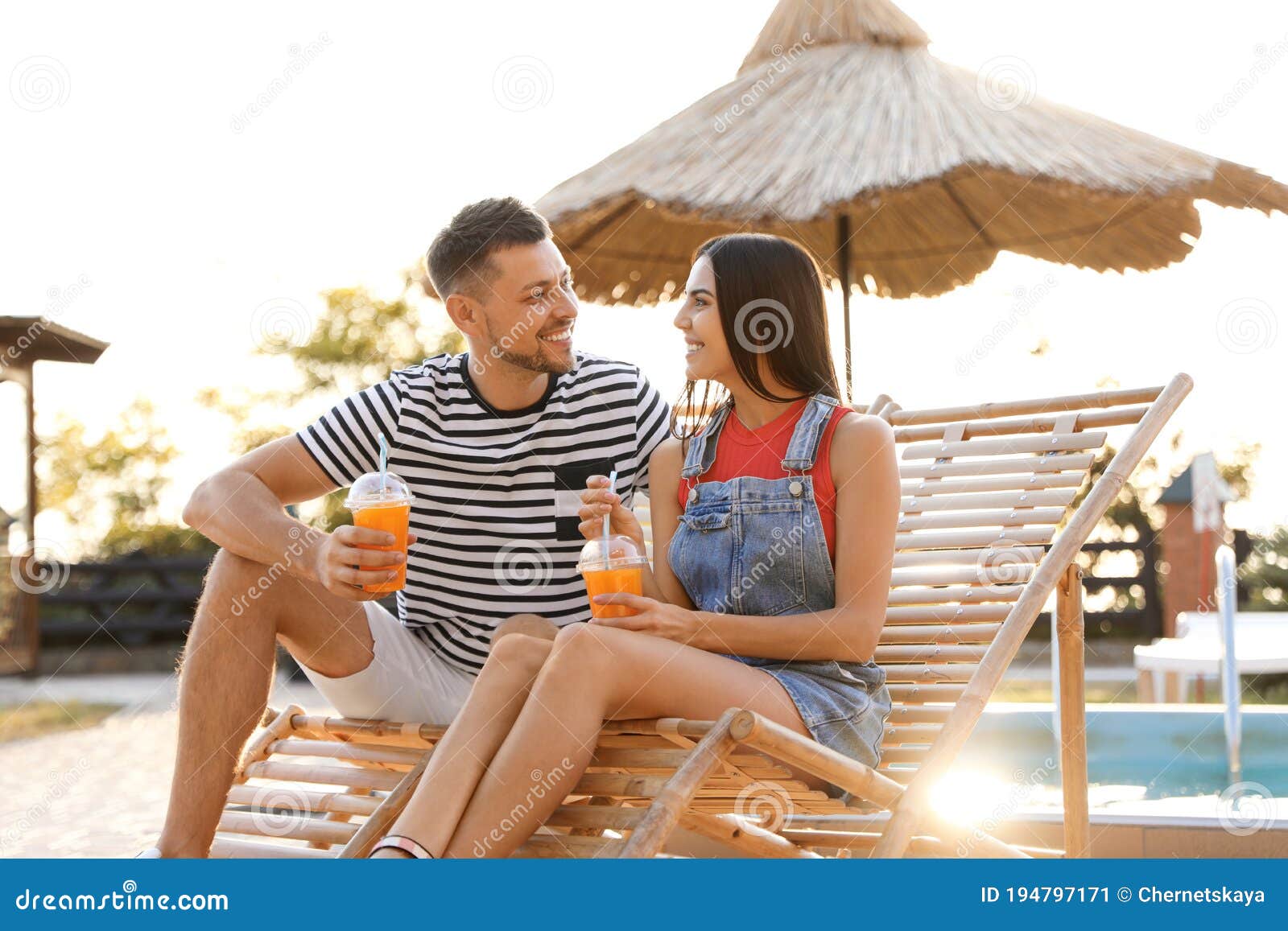 Couple with Cups of Refreshing Drink Resting in Deck Chairs Outdoors ...