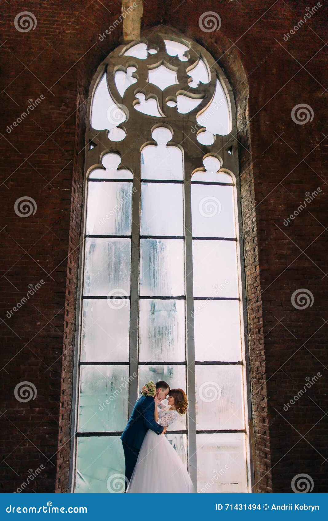 Happy Couple Embracing Holding Arms In The Front Of Old Gothic Window