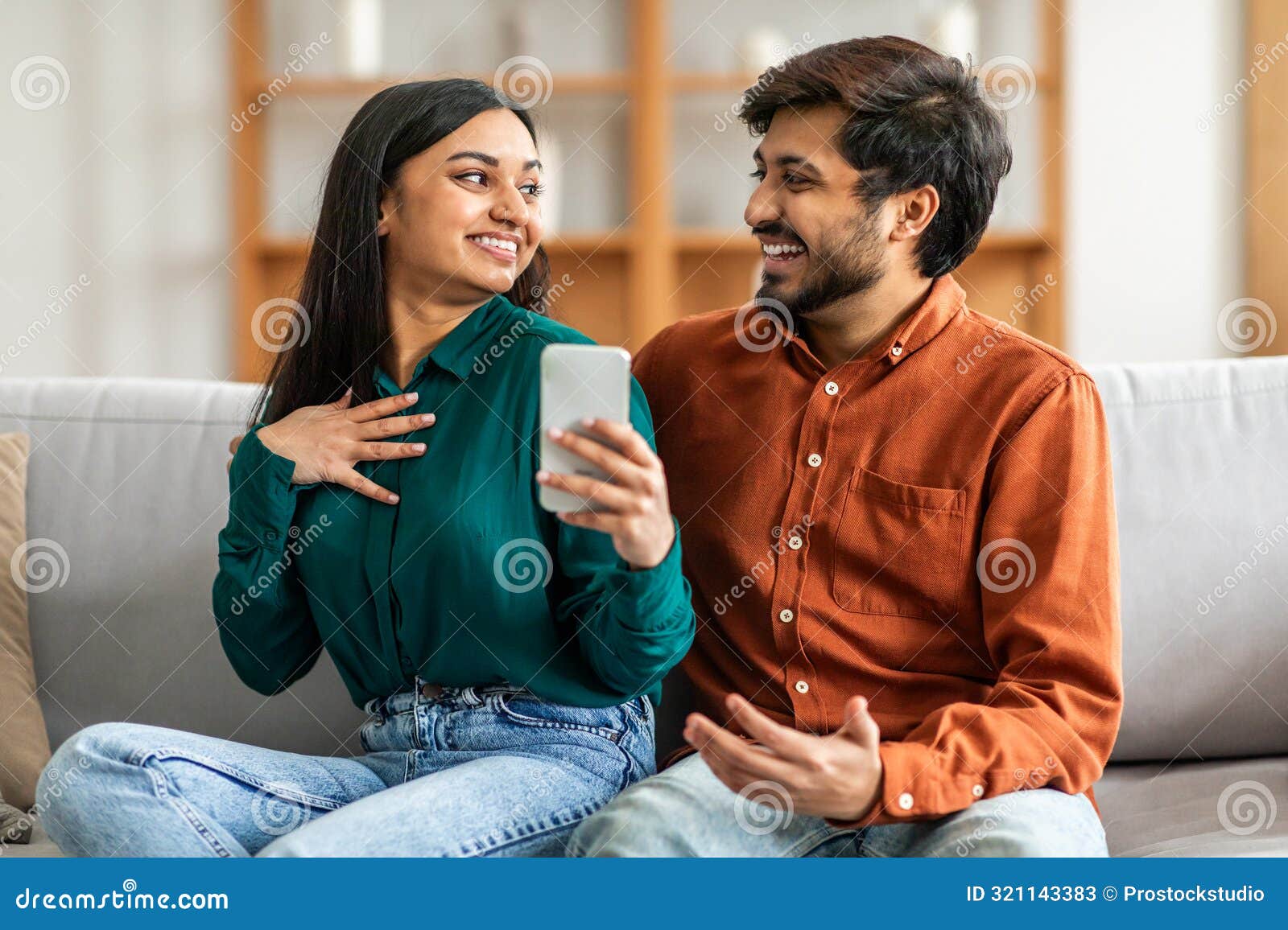 Happy Couple Sitting On Couch Looking At Cell Phone Stock Image Image