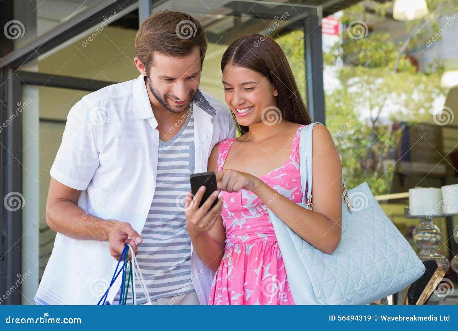 Happy Couple Smiling and Looking at Mobile Phone Stock Image - Image of ...