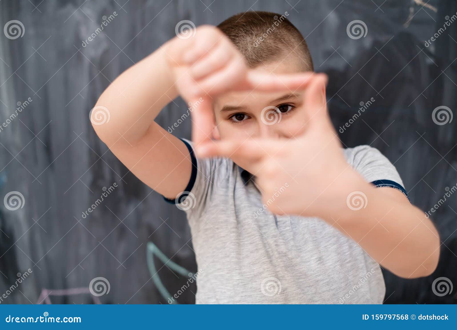 Happy Boy Making Hand Frame Gesture in Front of Chalkboard Stock Photo ...