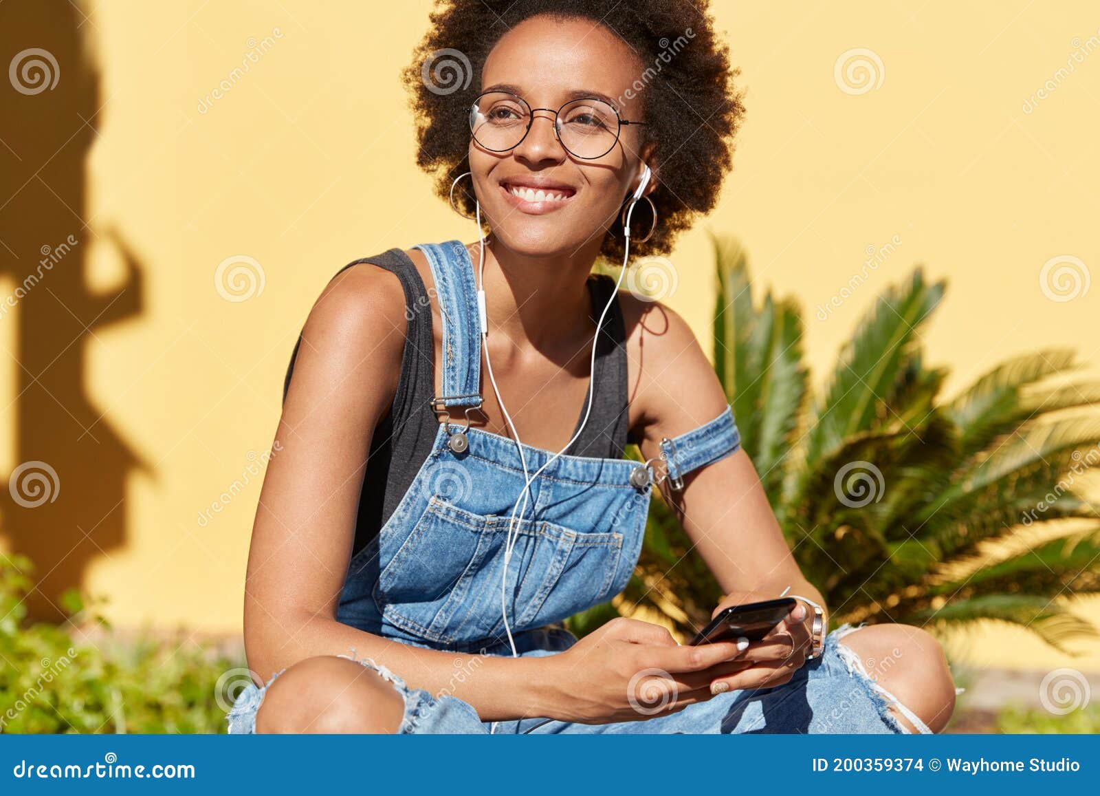Happy Dark Skinned Woman With Afro Haircut Uses App On Mobile Phone