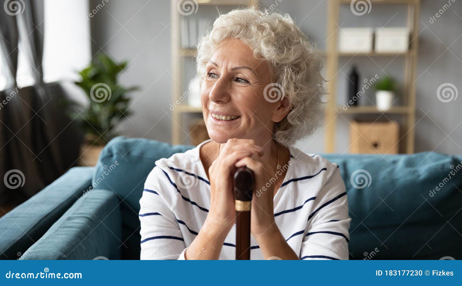 Happy Disabled Grandmother Holding Walking Stick Resting At Home