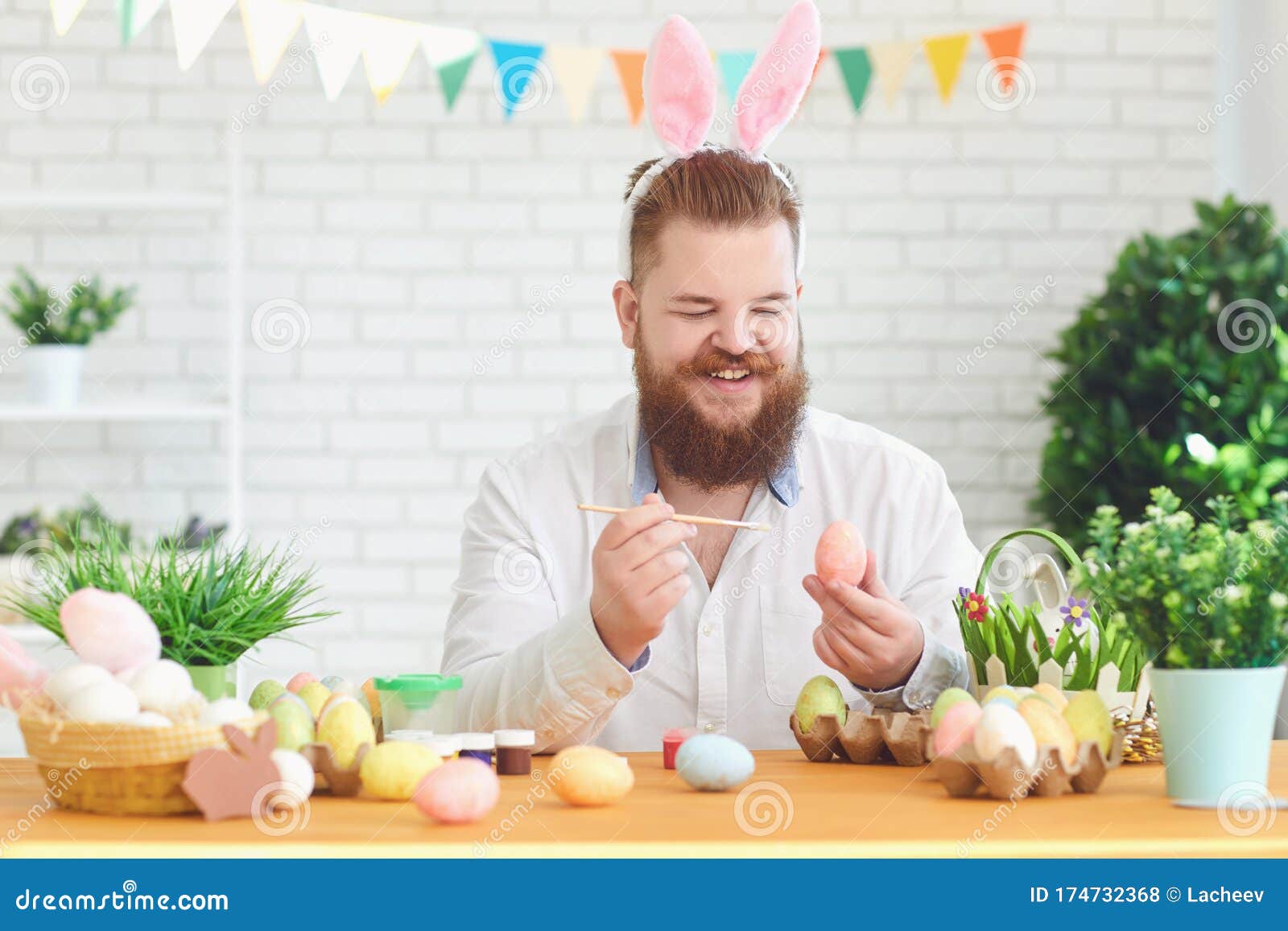 Happy Easter.a Funny Fat Man Decorates Eggs while Sitting at a Table ...