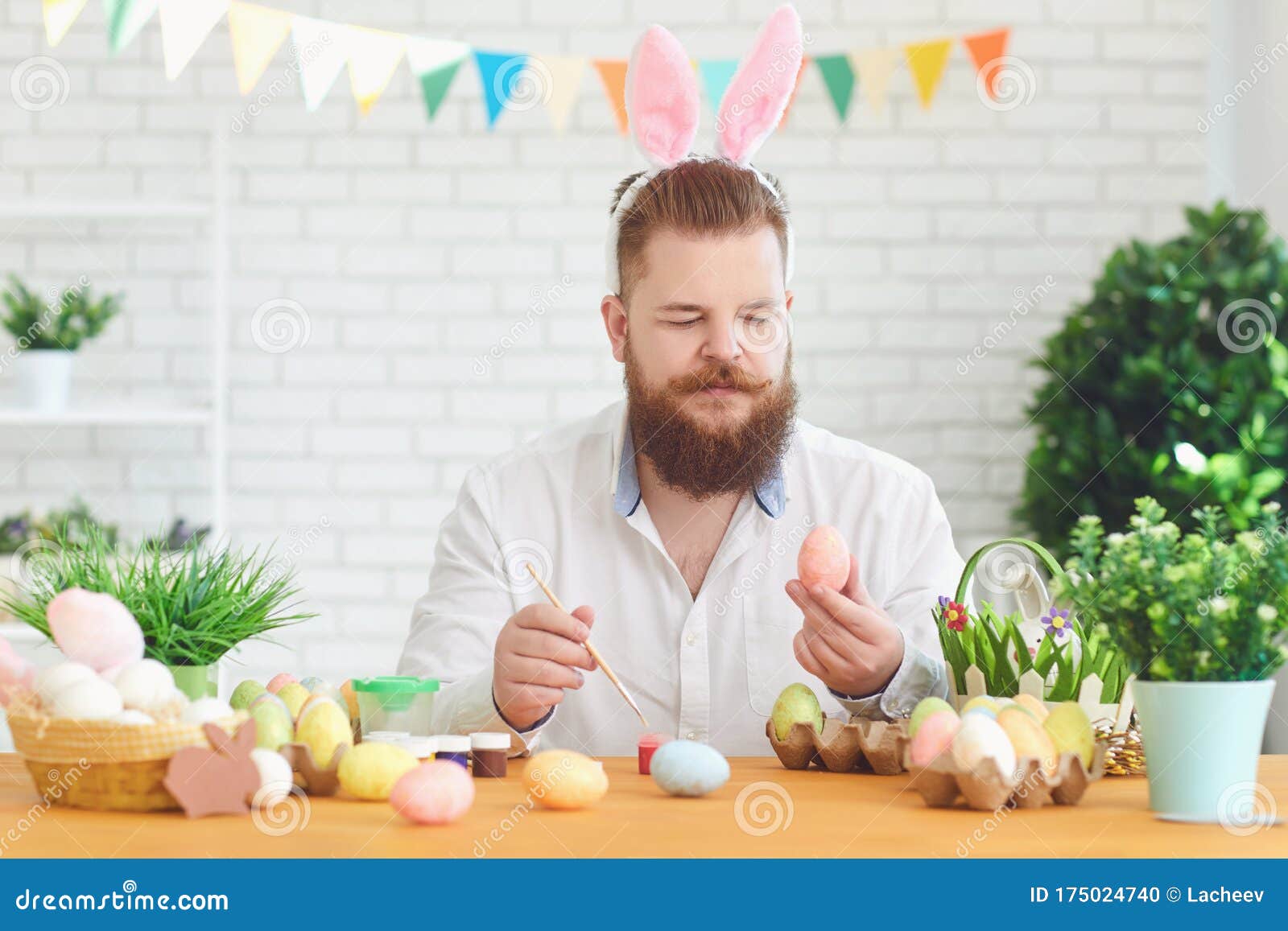 Happy Easter.a Funny Fat Man Decorates Eggs while Sitting at a Table ...