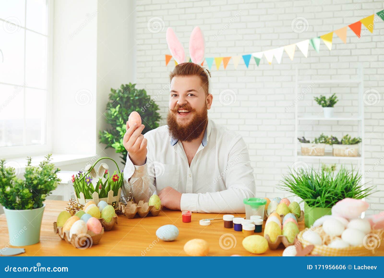 Happy Easter.a Funny Fat Man Decorates Eggs while Sitting at a Table ...