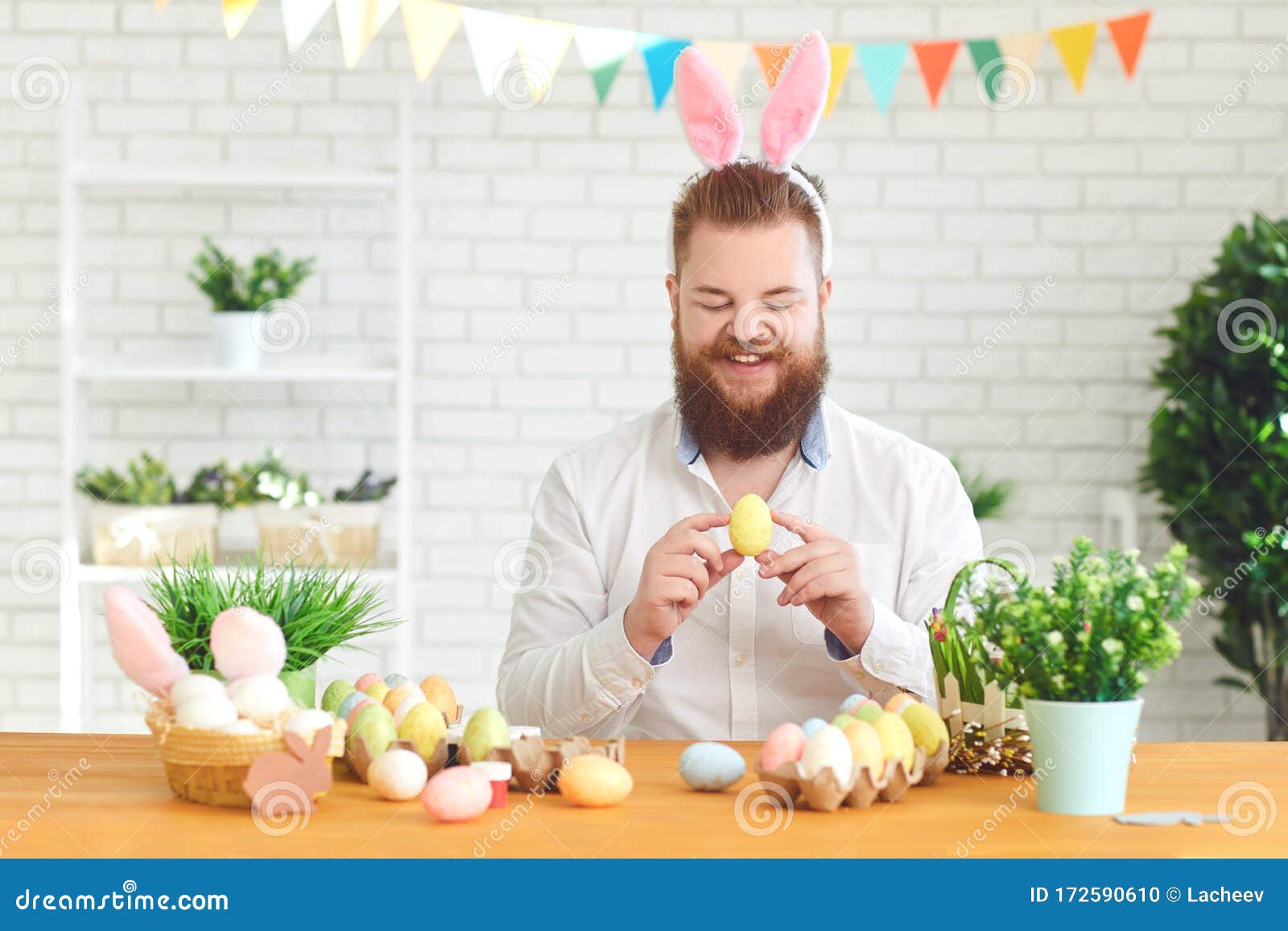 Happy Easter.a Funny Fat Man Decorates Eggs while Sitting at a Table ...