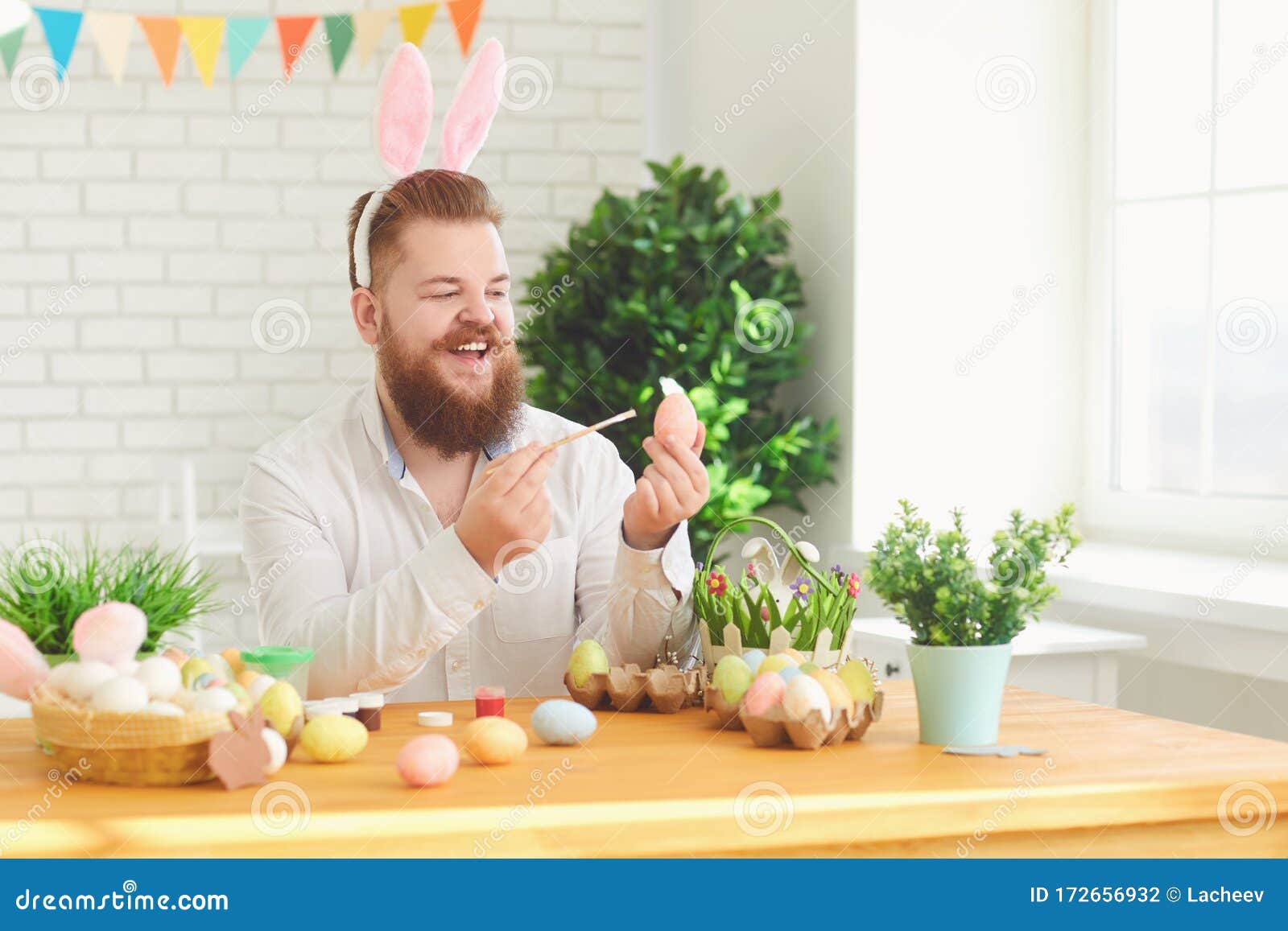 Happy Easter.a Funny Fat Man Decorates Eggs while Sitting at a Table ...
