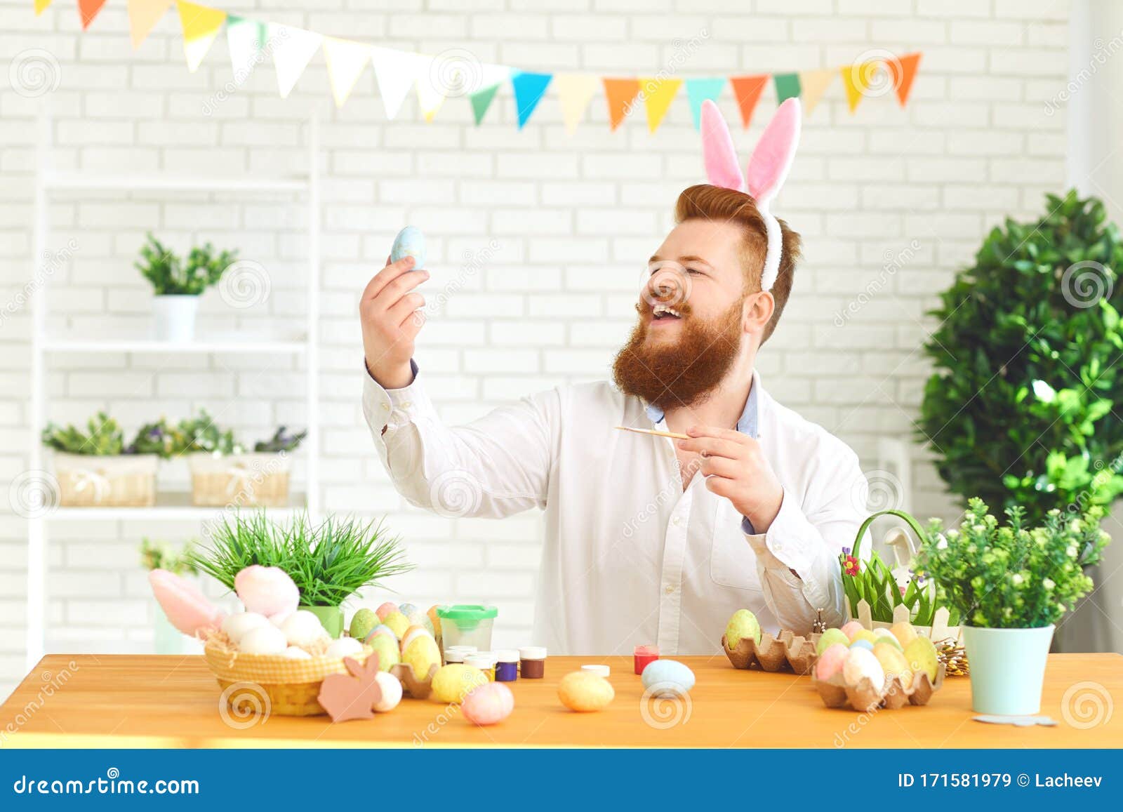 Happy Easter.a Funny Fat Man Decorates Eggs while Sitting at a Table ...