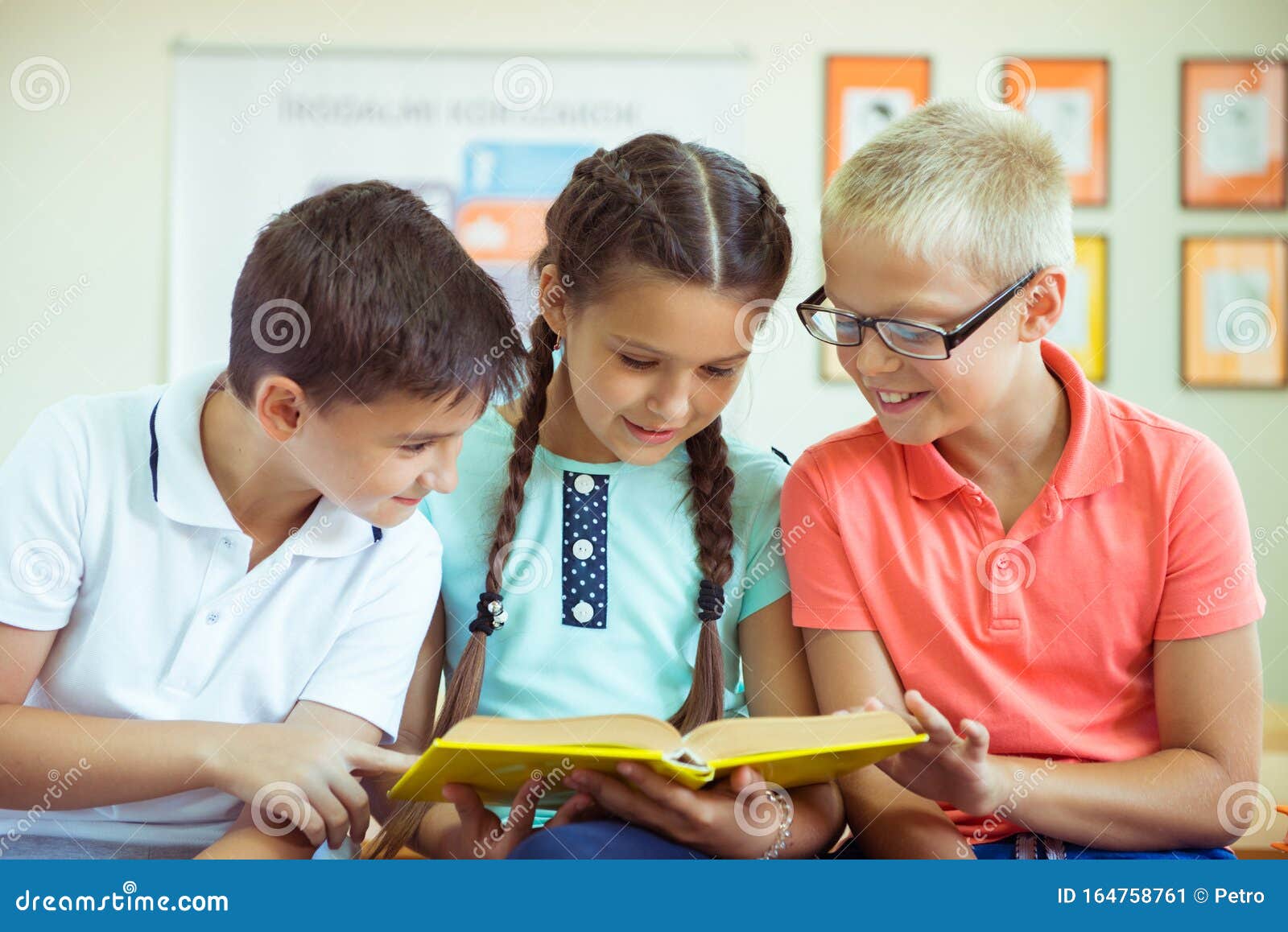 Happy Elementary Students Sitting on Desk with Book and Discussing in ...