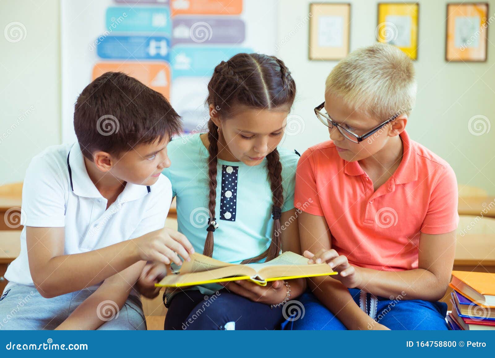 Happy Elementary Students Sitting on Desk with Book and Discussing in ...