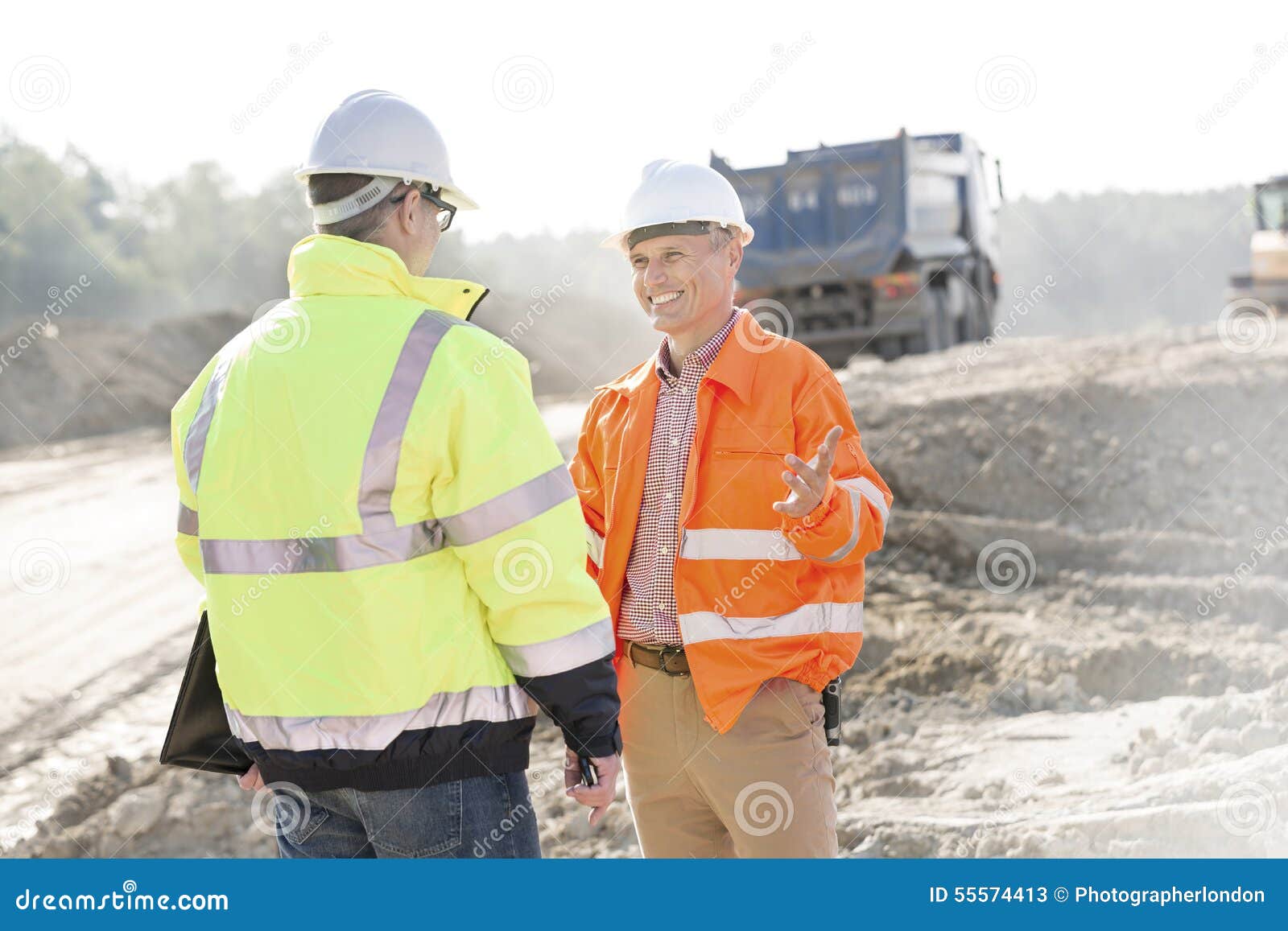 Happy Engineer Talking To Colleague at Construction Site on Sunny Day ...