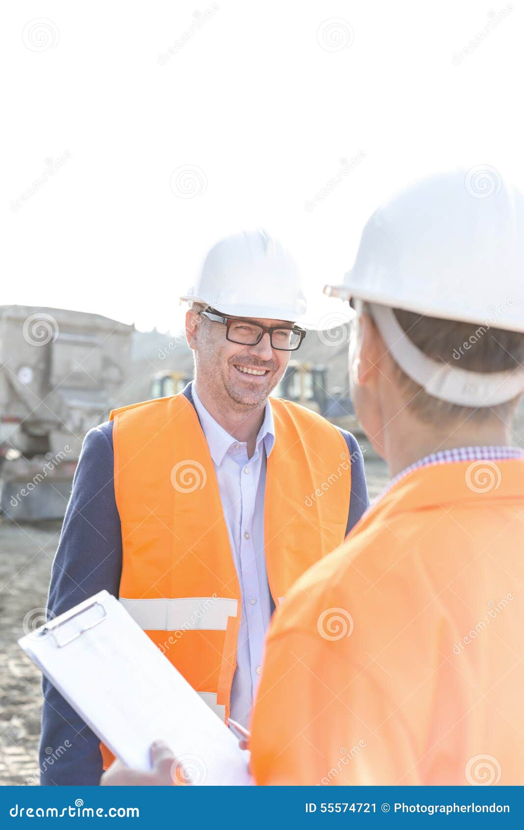 Happy Engineers Discussing at Construction Site Against Clear Sky Stock ...