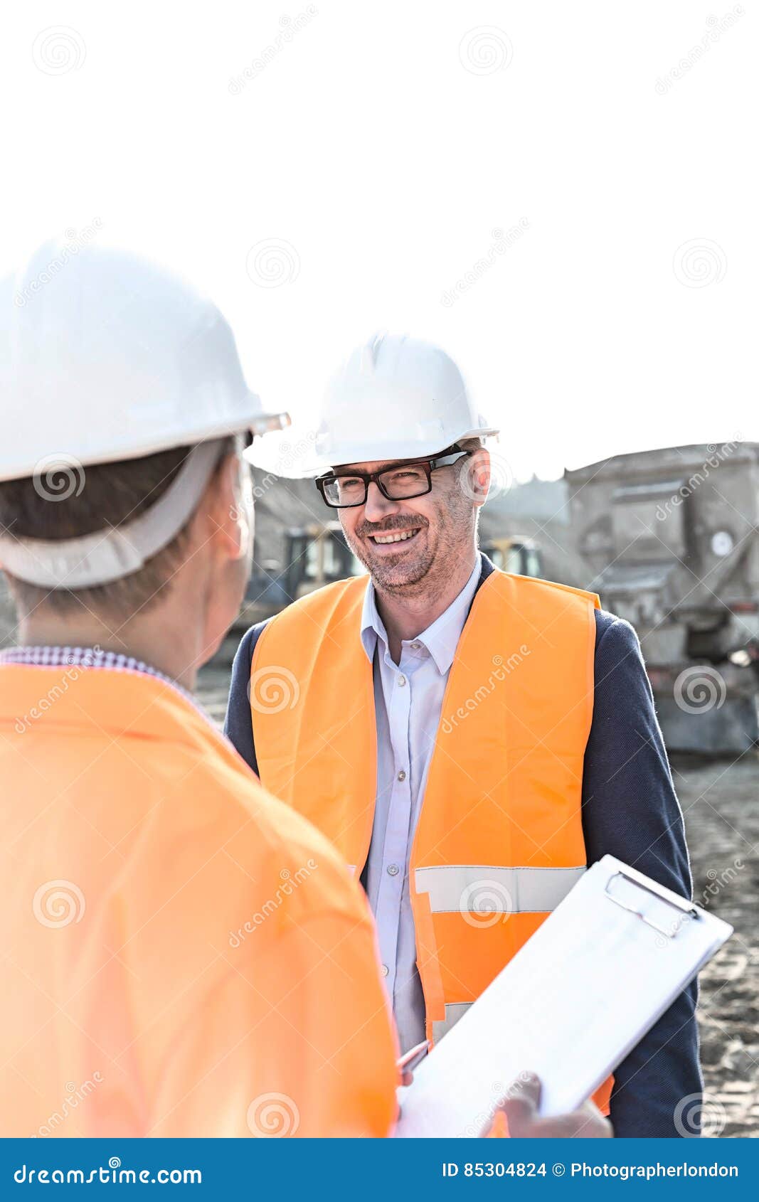 Happy Engineers Discussing at Construction Site Against Clear Sky Stock ...