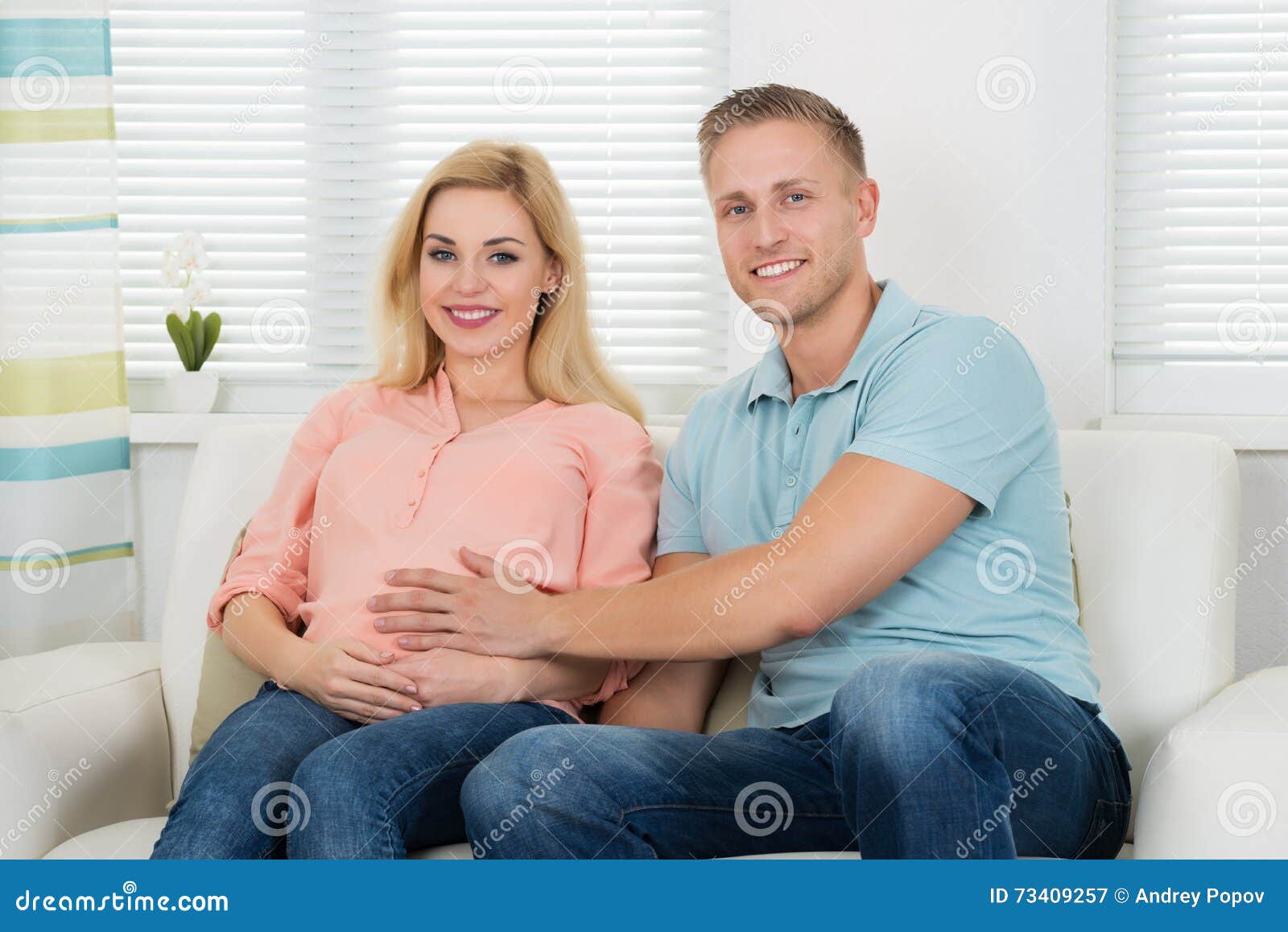 Happy Expectant Couple Sitting on Sofa at Home Stock Image - Image of ...