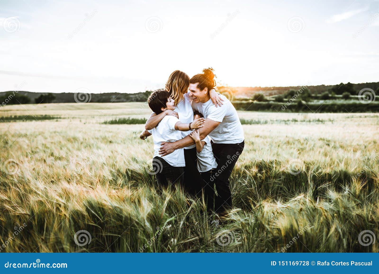 Happy Family Hugging in the Field and Smiling. Family in a Sunset Stock ...