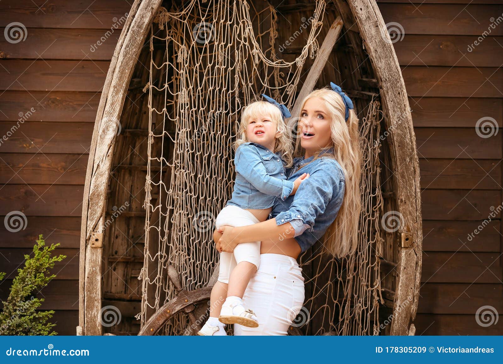 Blonde Mother Hugging Back View Daughter And Wearing White Dress
