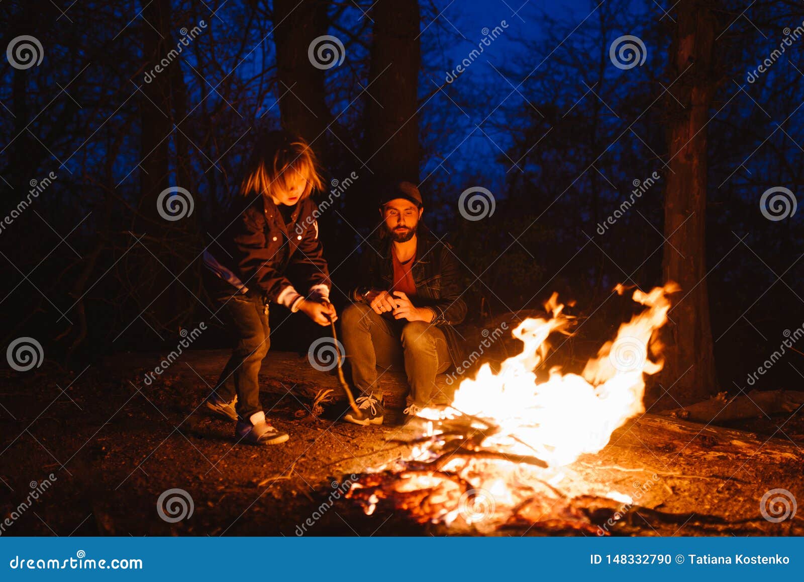 Happy Father and His Son Sitting Outside in Front of a Fire and Looking ...