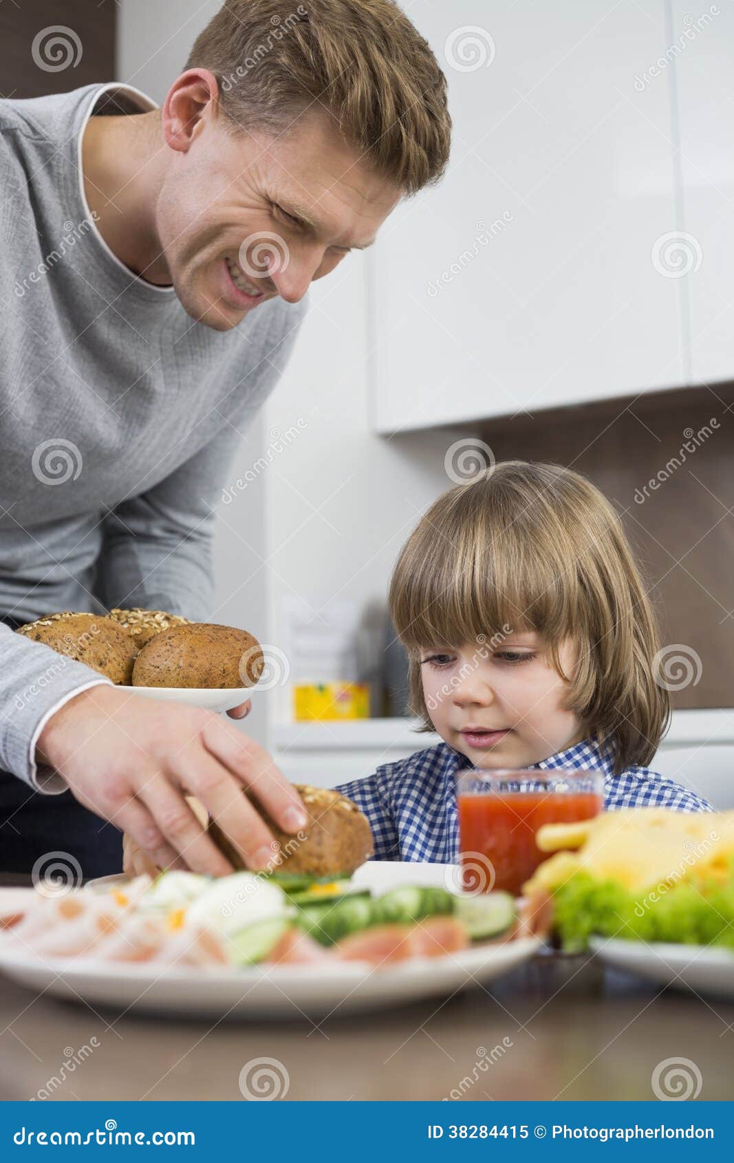 Happy Father Serving Meal To Son At Table In Kitchen Stock Photo ...