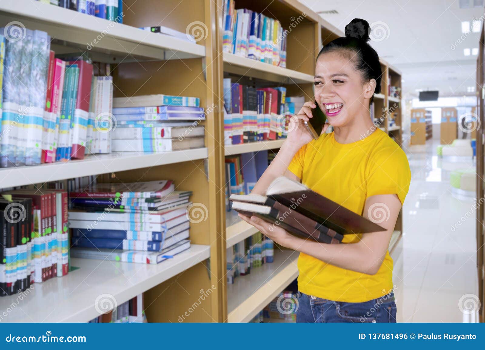 Happy Female College Student with Phone in Library Stock Photo - Image ...