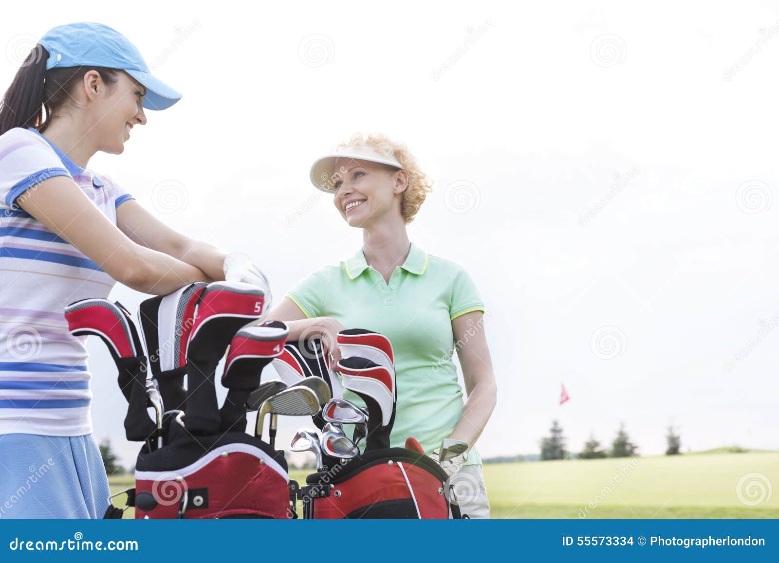 Happy Female Golfers Talking at Golf Course Against Clear Sky Stock ...
