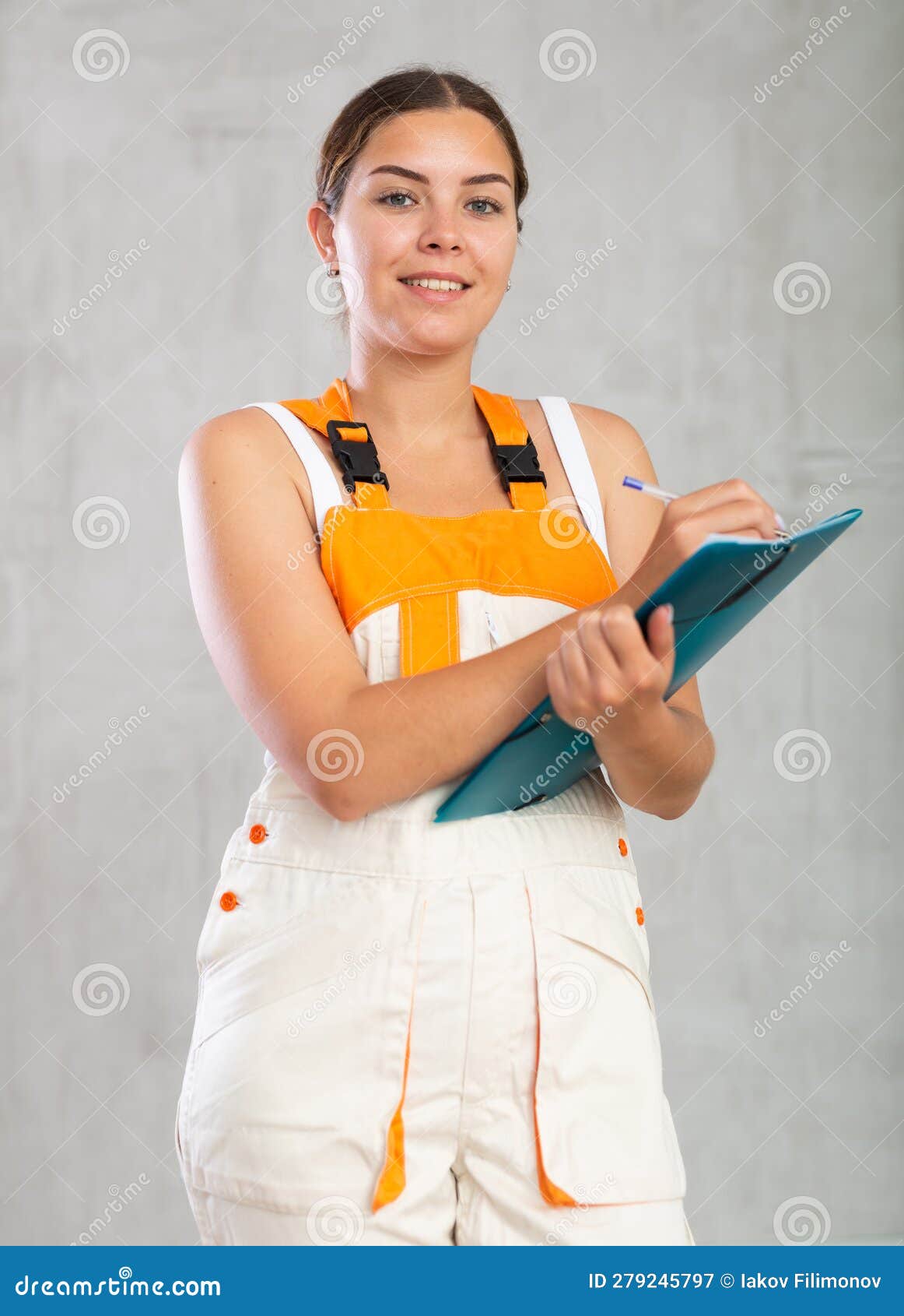 Happy Female Worker in Work Clothes Making Notes in File with Papers ...